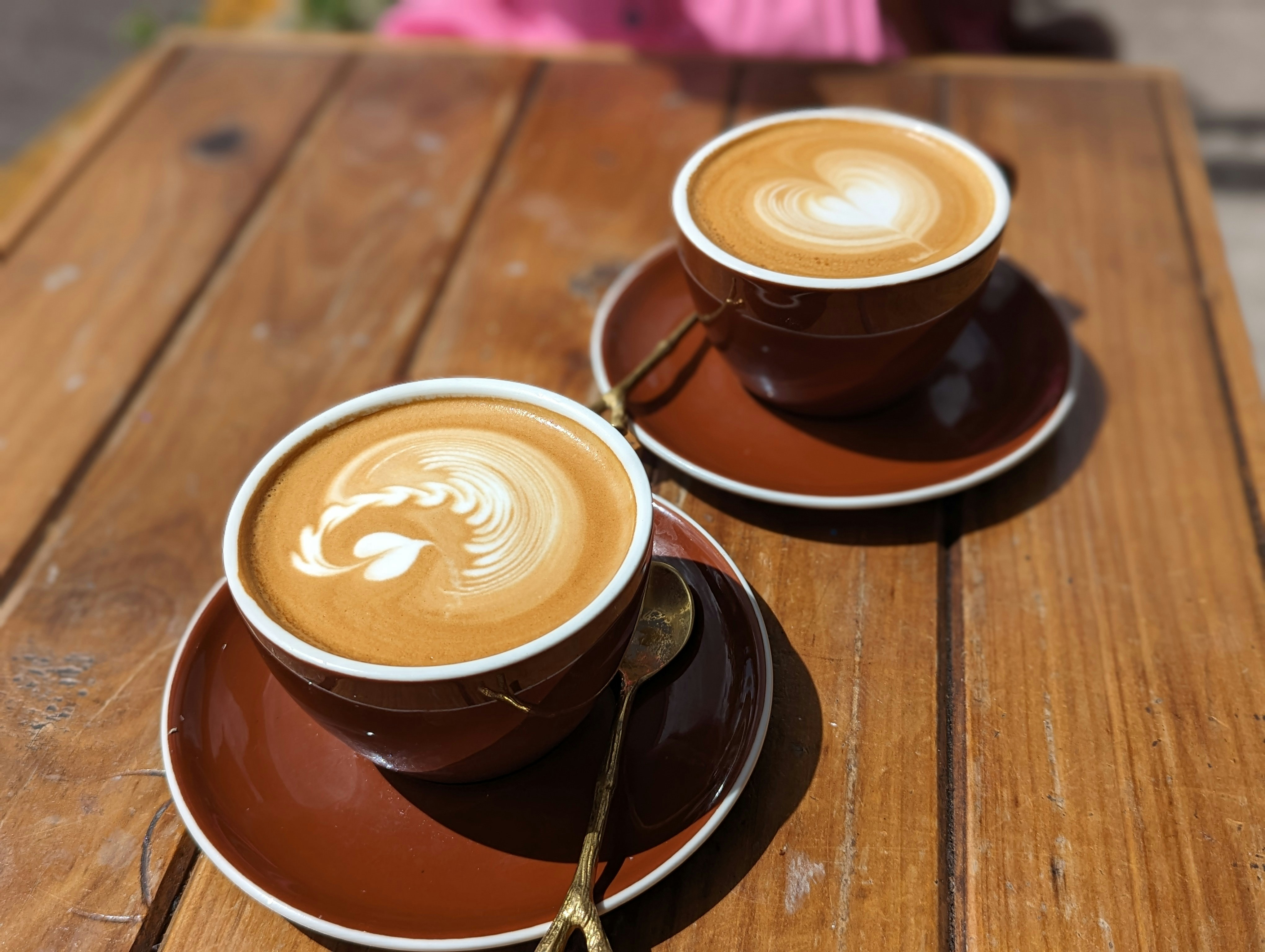 Two cups of coffee with latte art on a wooden table.