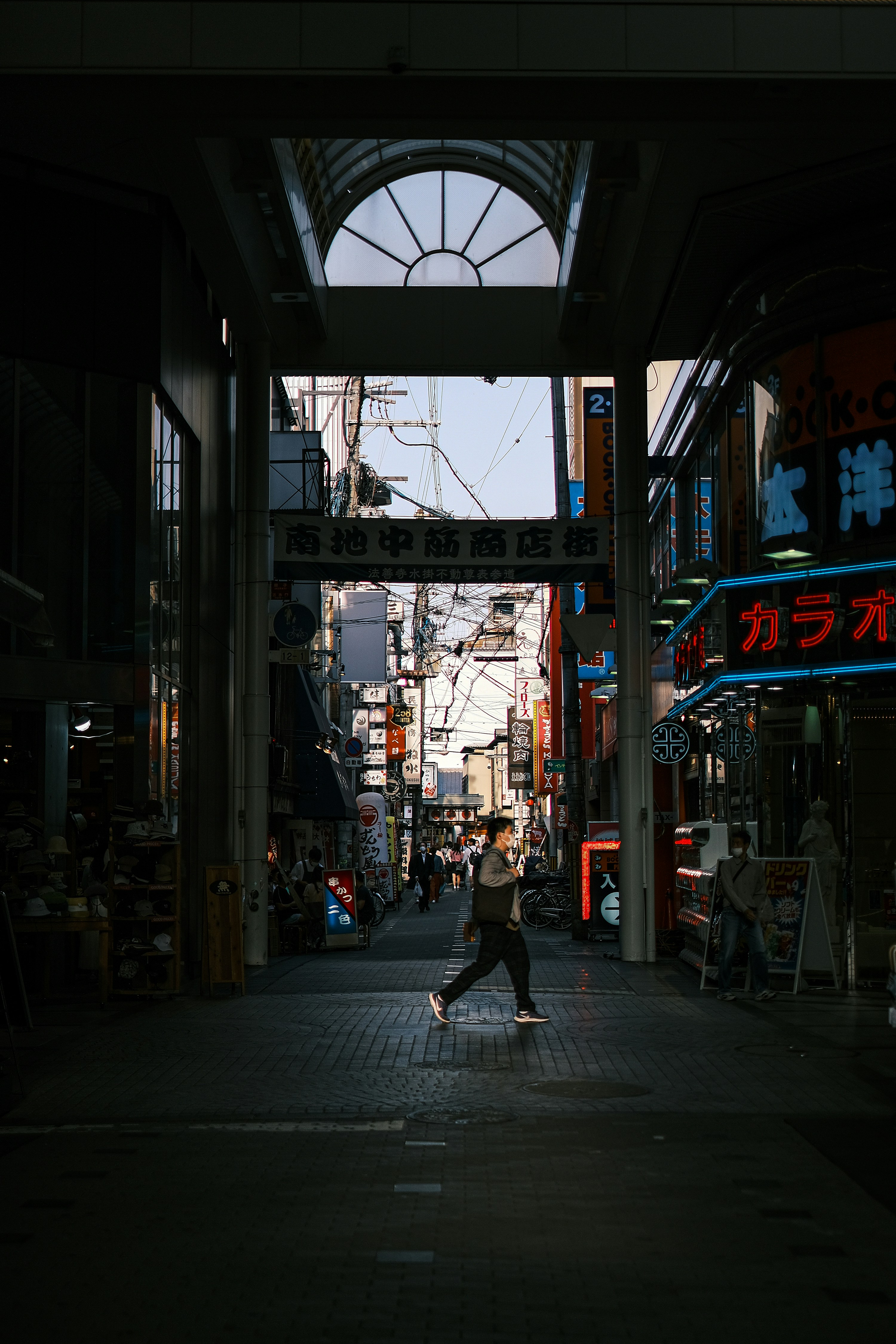 Crossing Neon Shadows in a Covered Tokyo Arcade