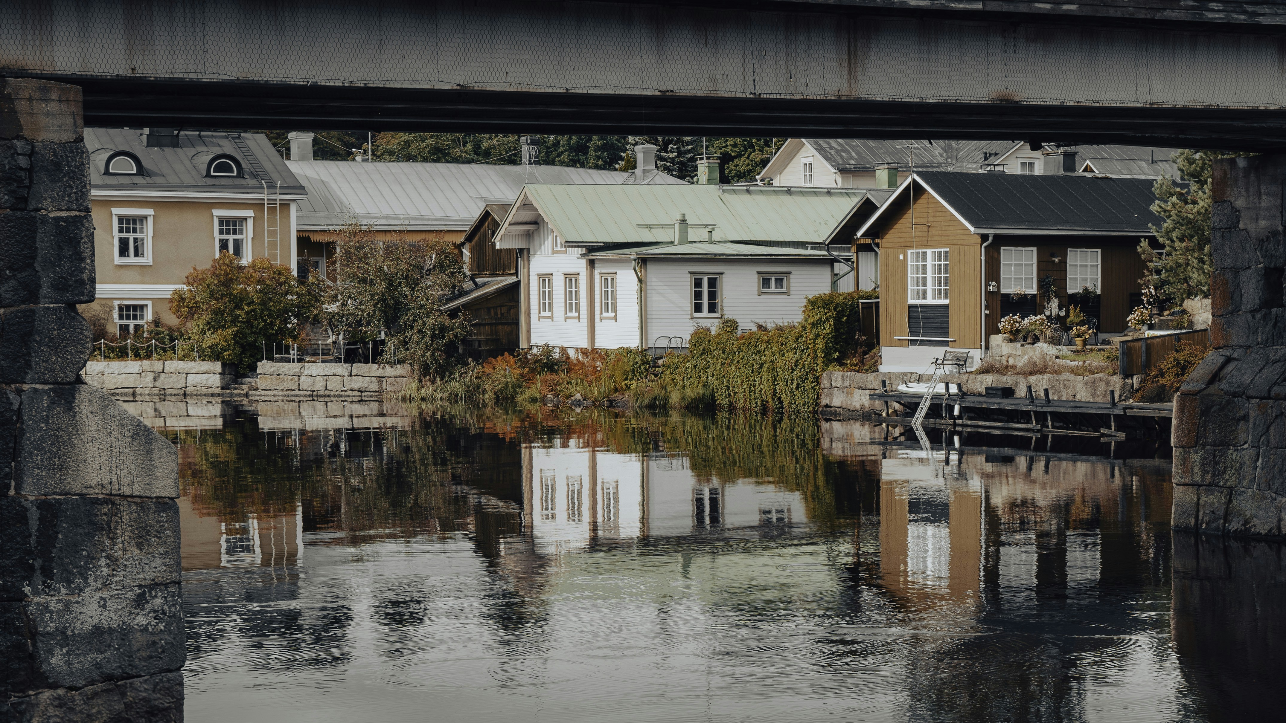 A bridge over a body of water with houses in the background