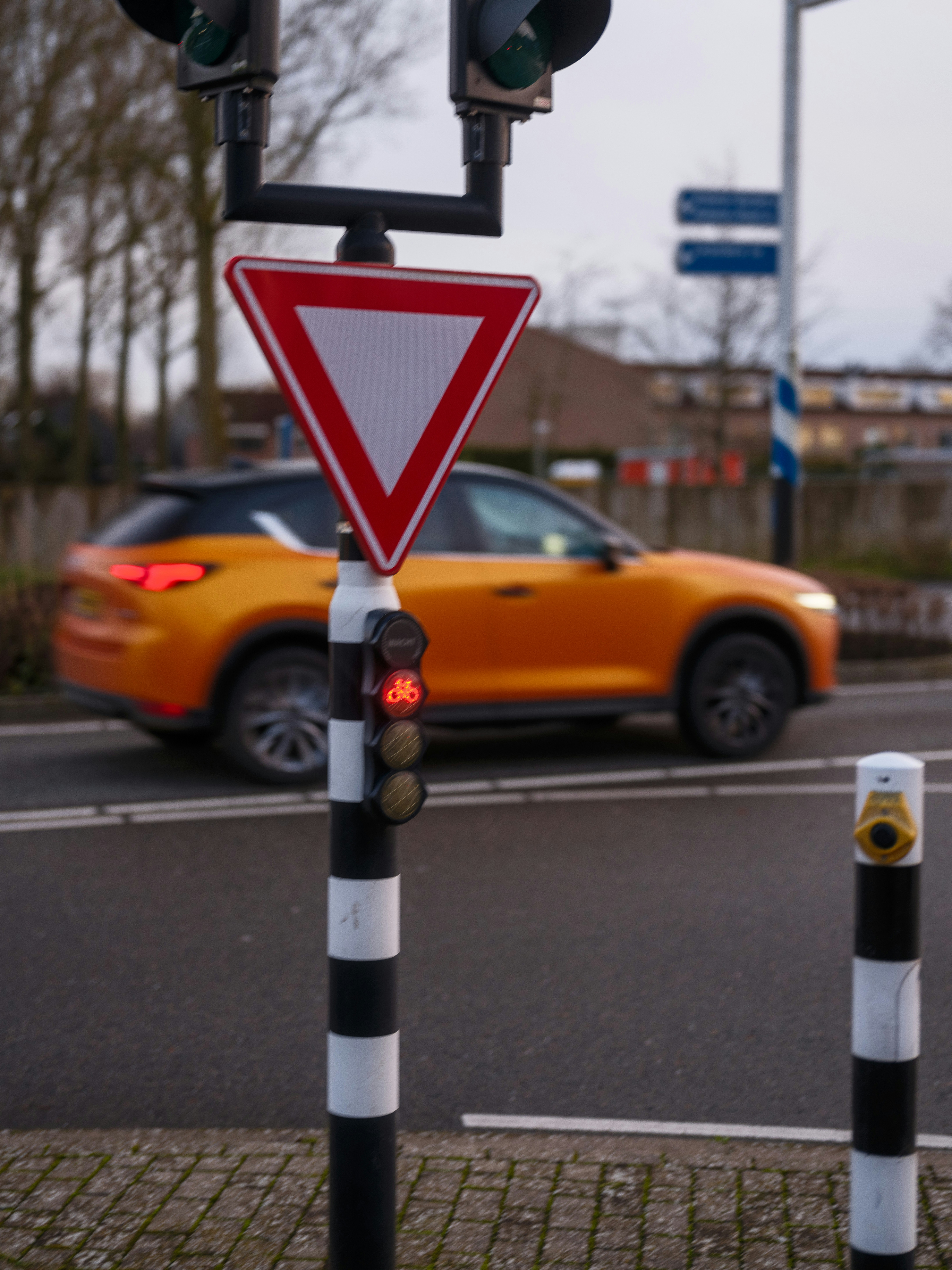 Close-Up Yield Sign Framed by a Blurred Yellow SUV at a Street Junction