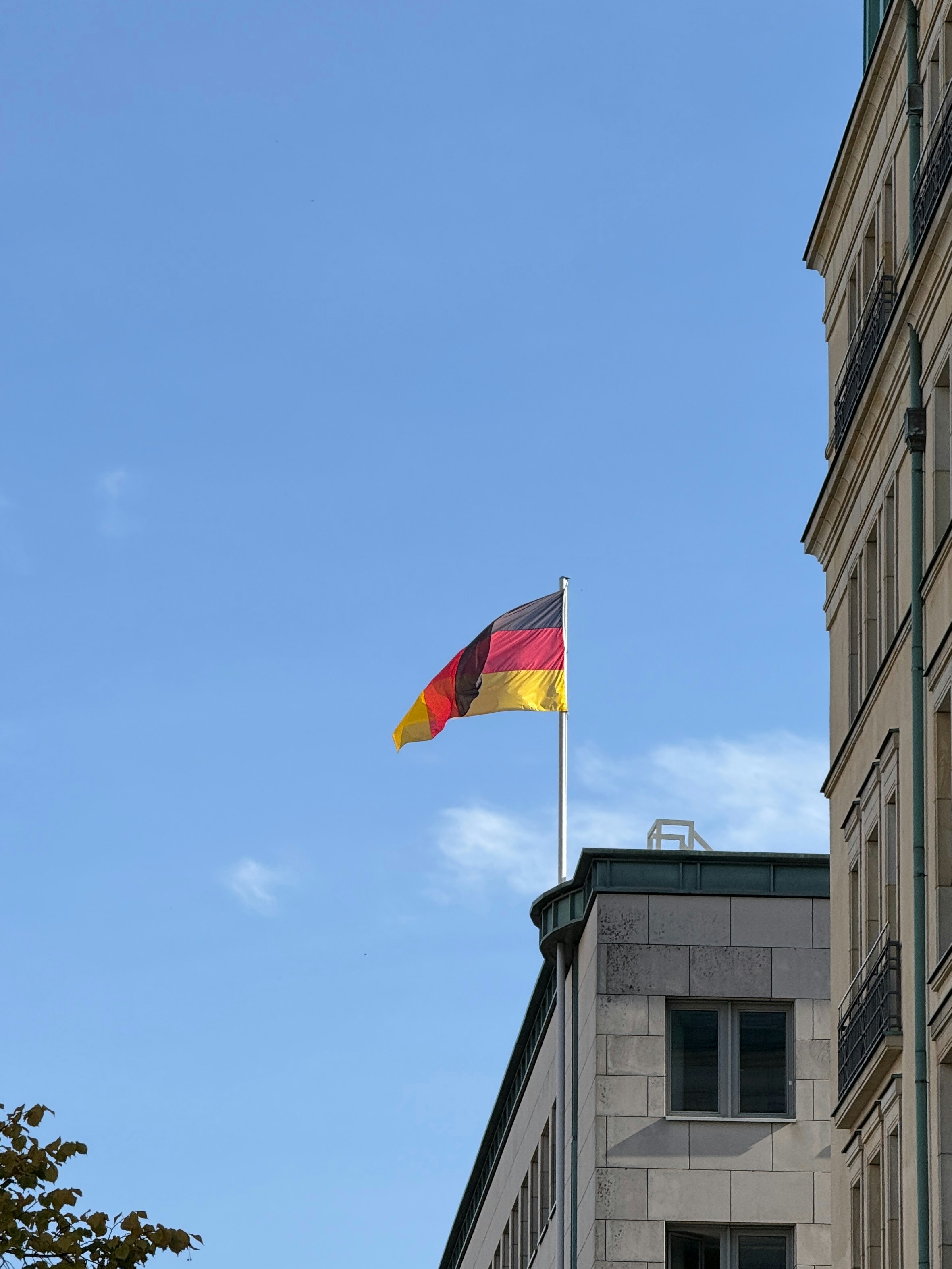 German Tricolor Flag Above a Sunlit City Facade