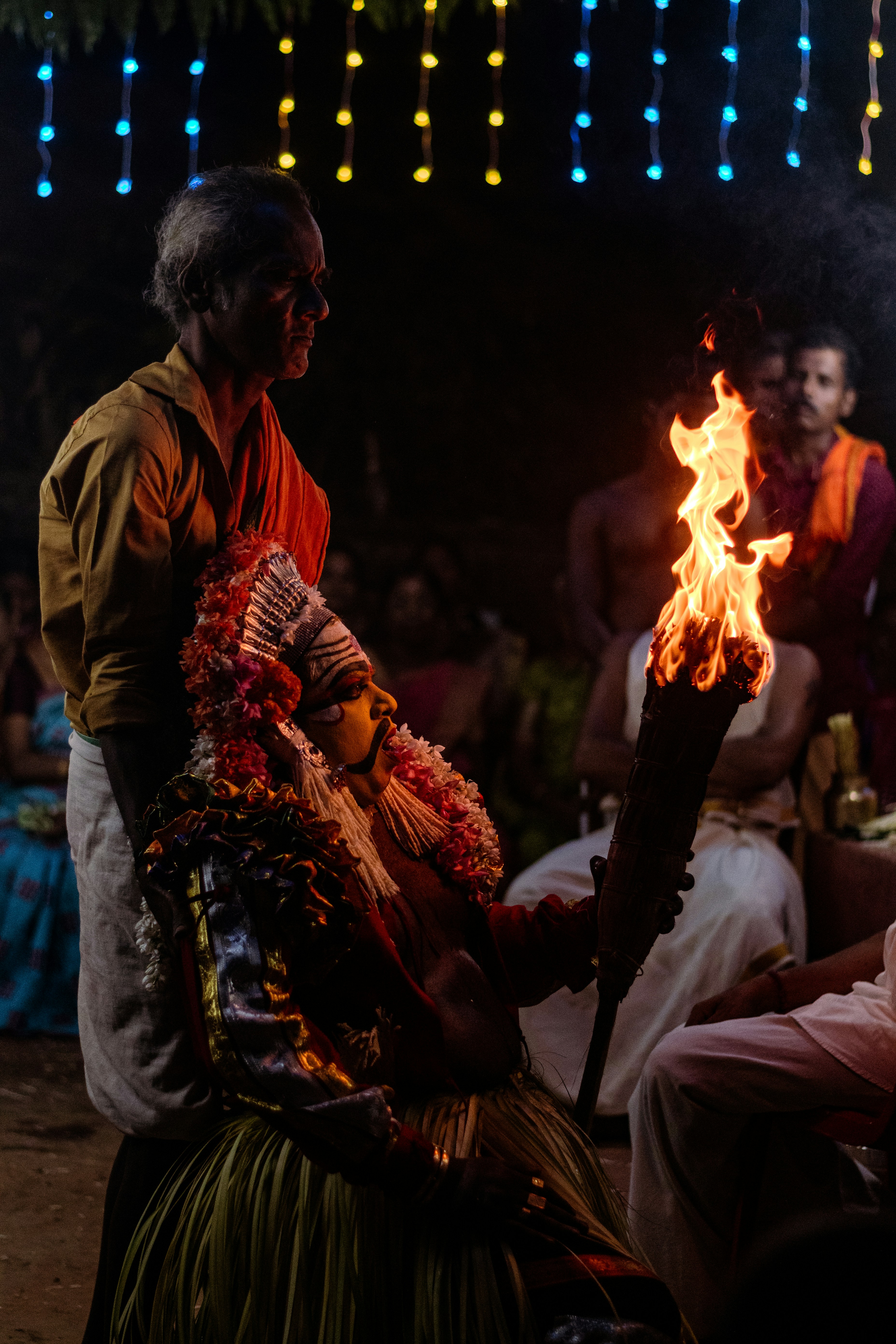 Torchbearer Amid Garlands: Night Ritual Under Fairy Lights
