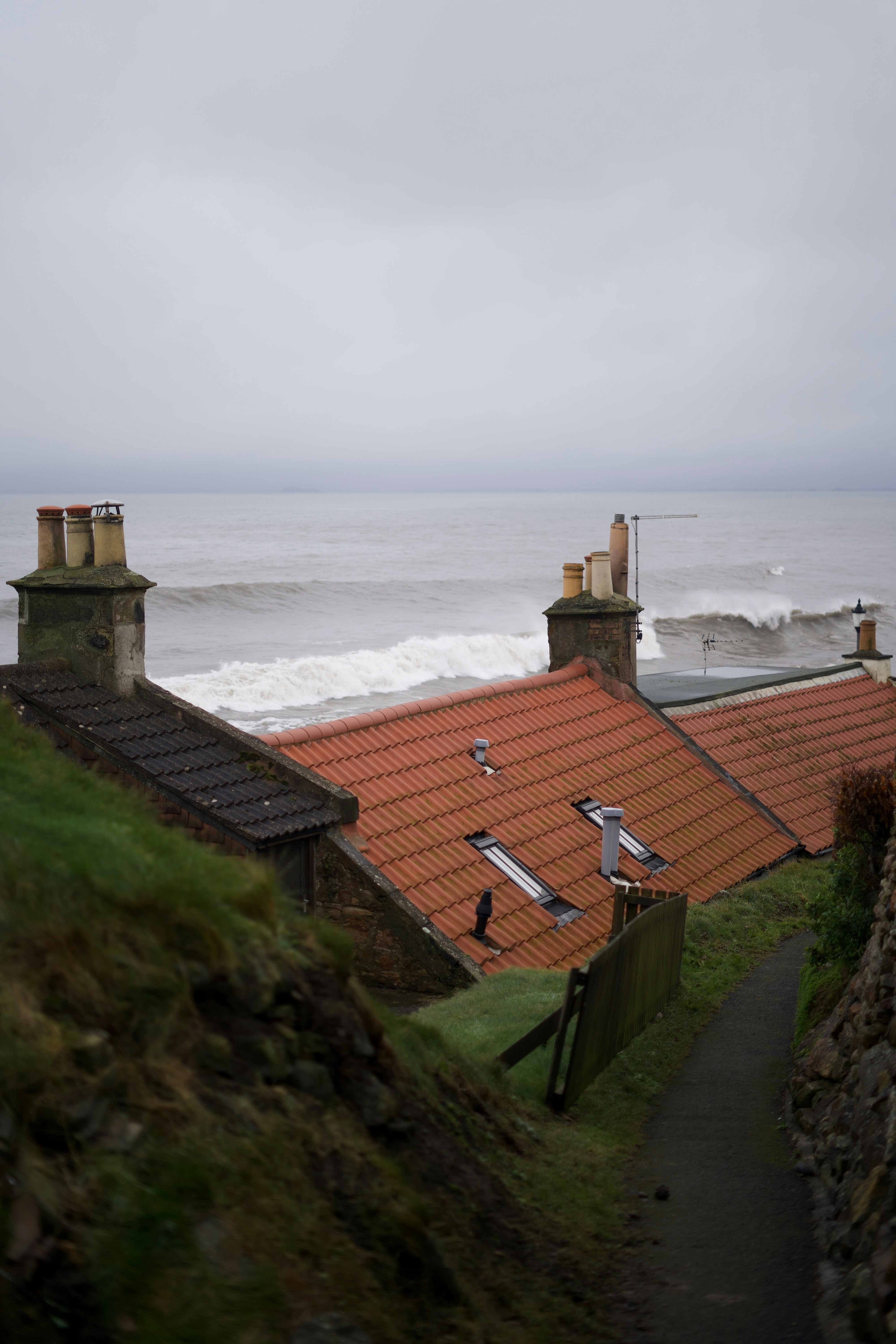 Red Roofs Descend Toward a Distant Sea Under an Overcast Sky