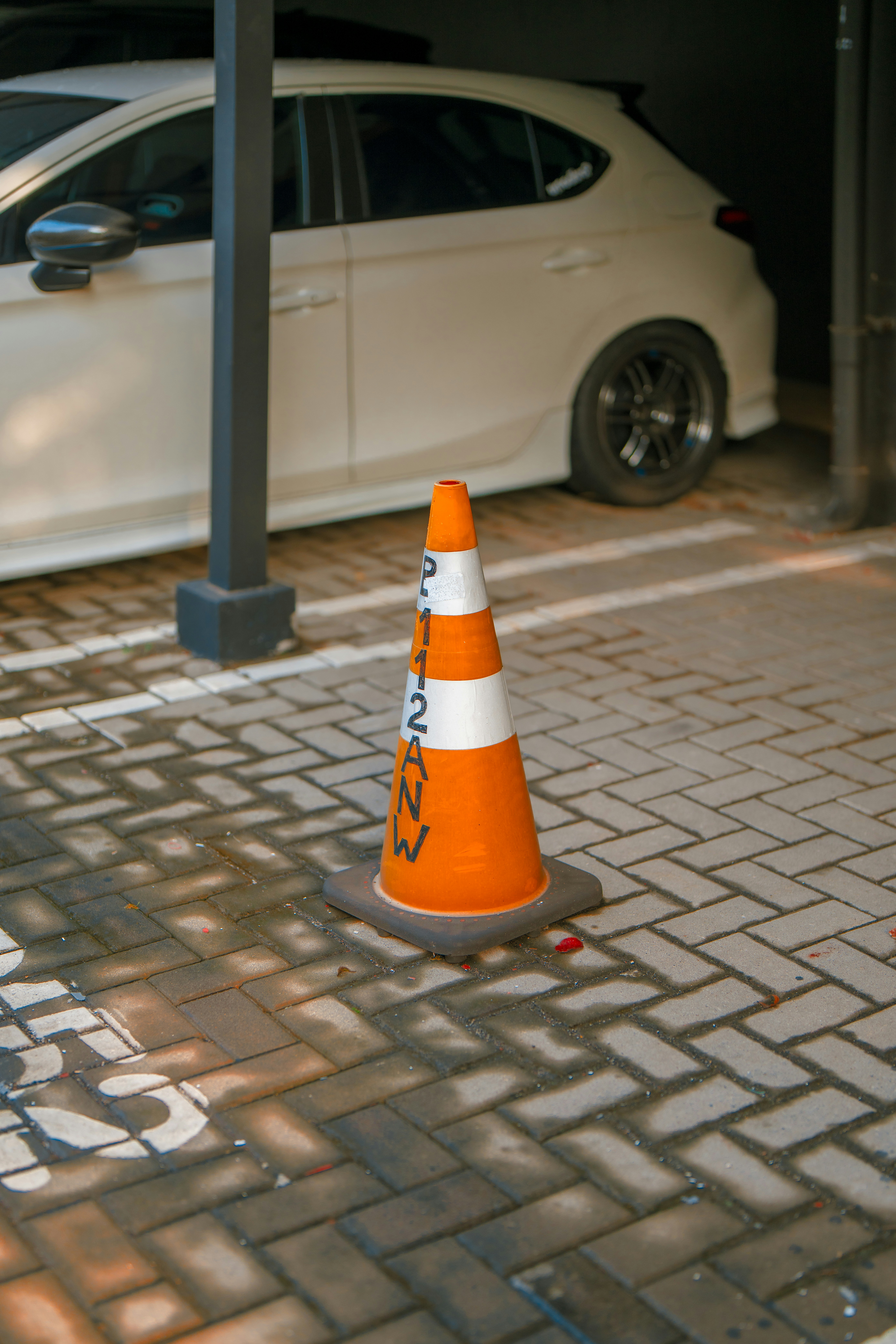 A white car parked in a garage next to a traffic cone photo – Free ...
