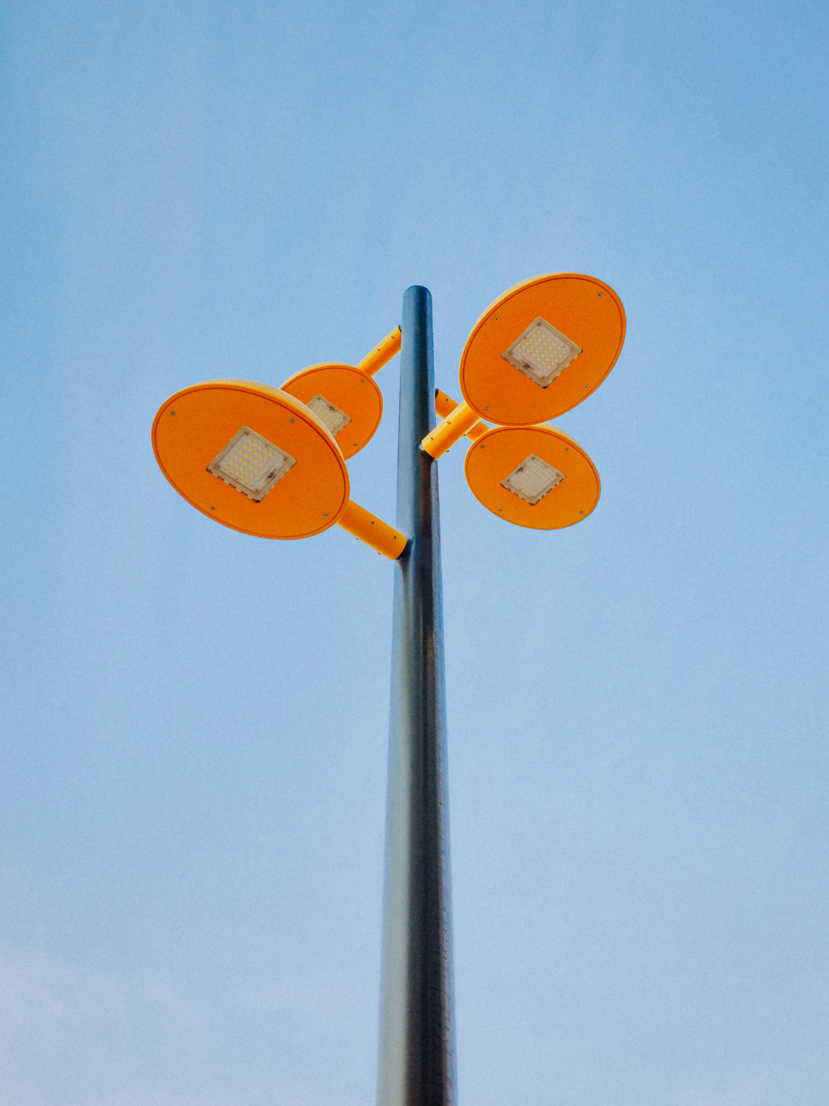 Orange Halo Cluster on a Steel Pole Under a Clear Blue Sky