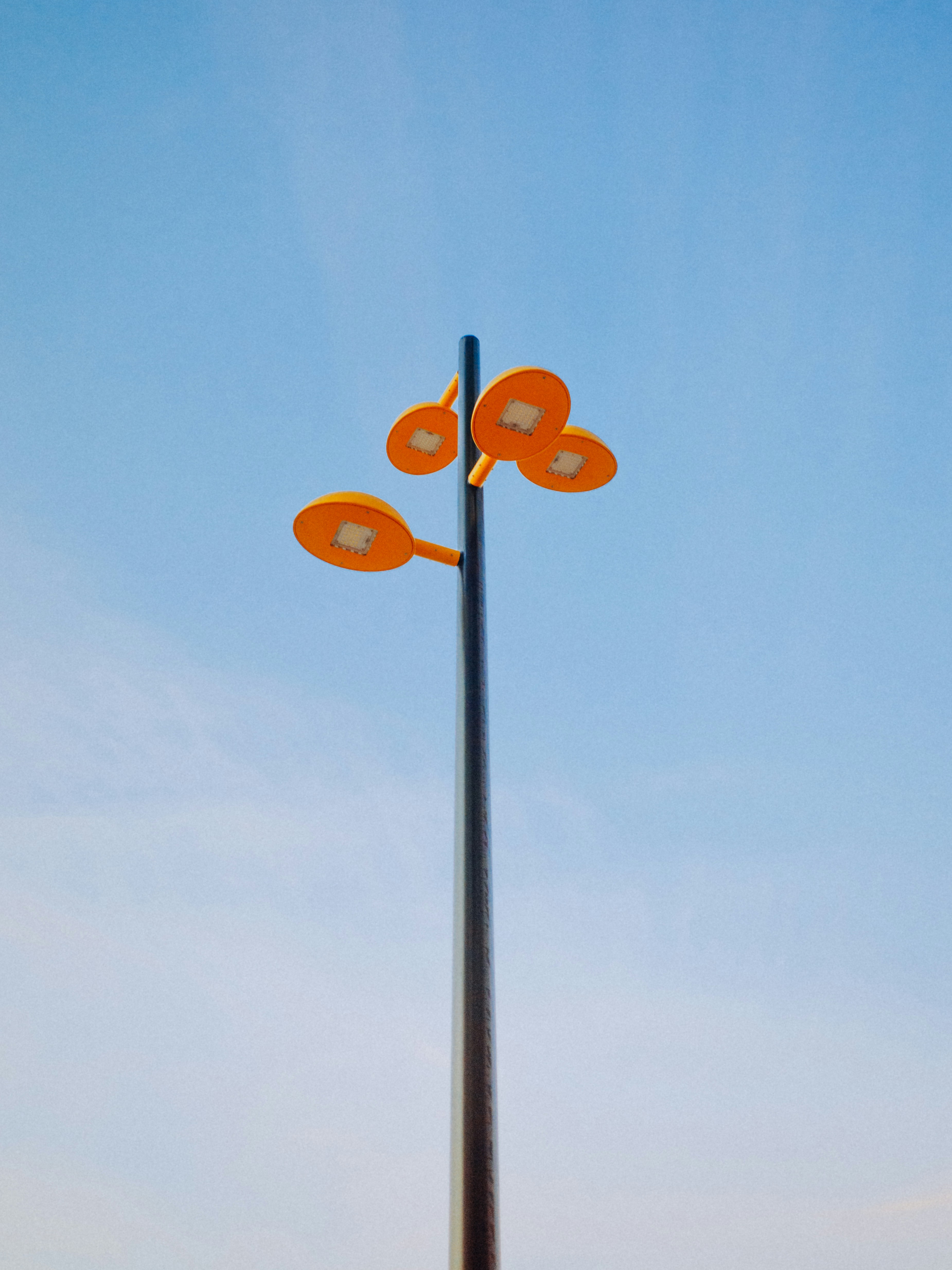 Blue Sky, Orange Heads: A Minimalist Street-Lamp Portrait