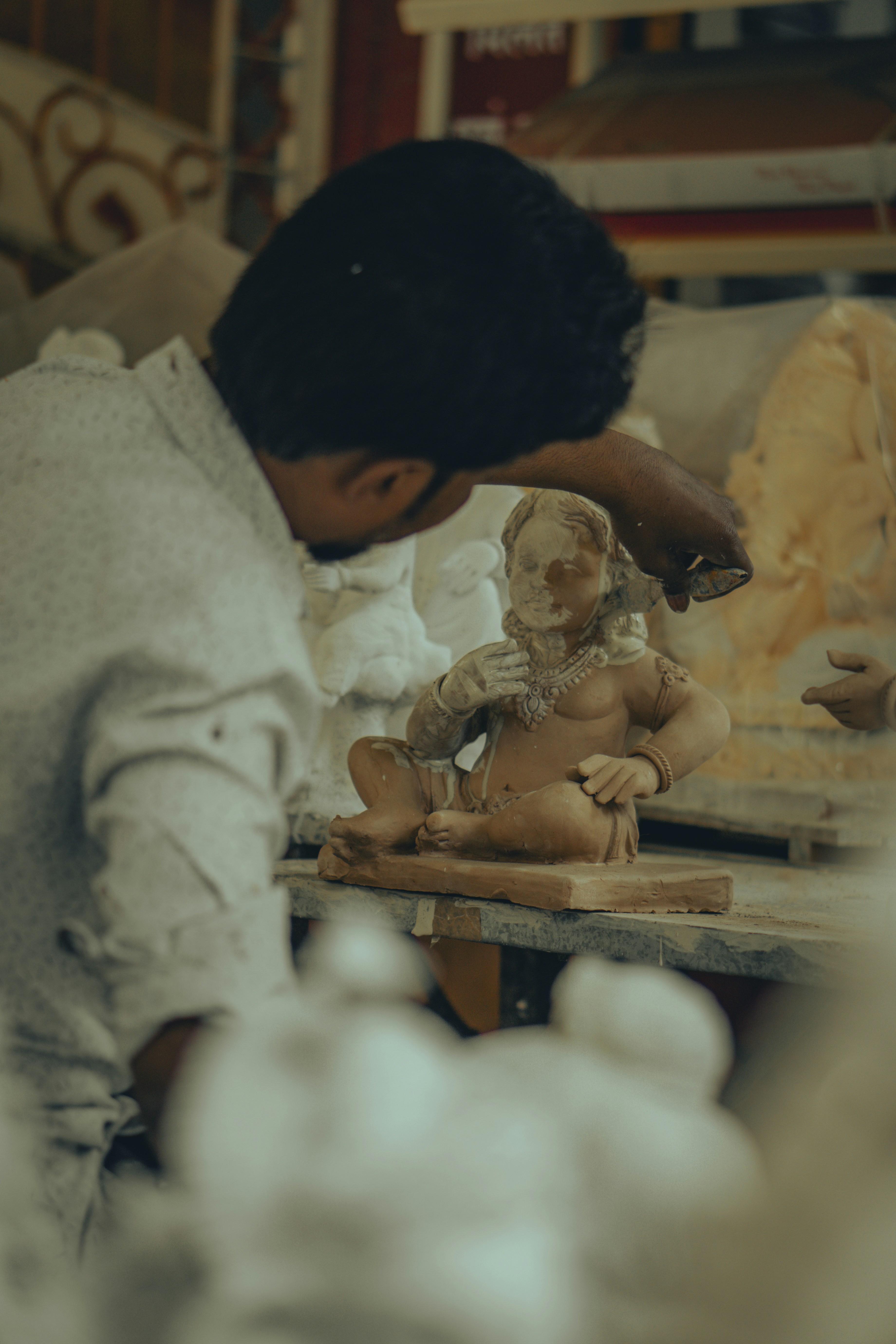 Beside the Clay Saint: a potter at work shaping a sacred figurine