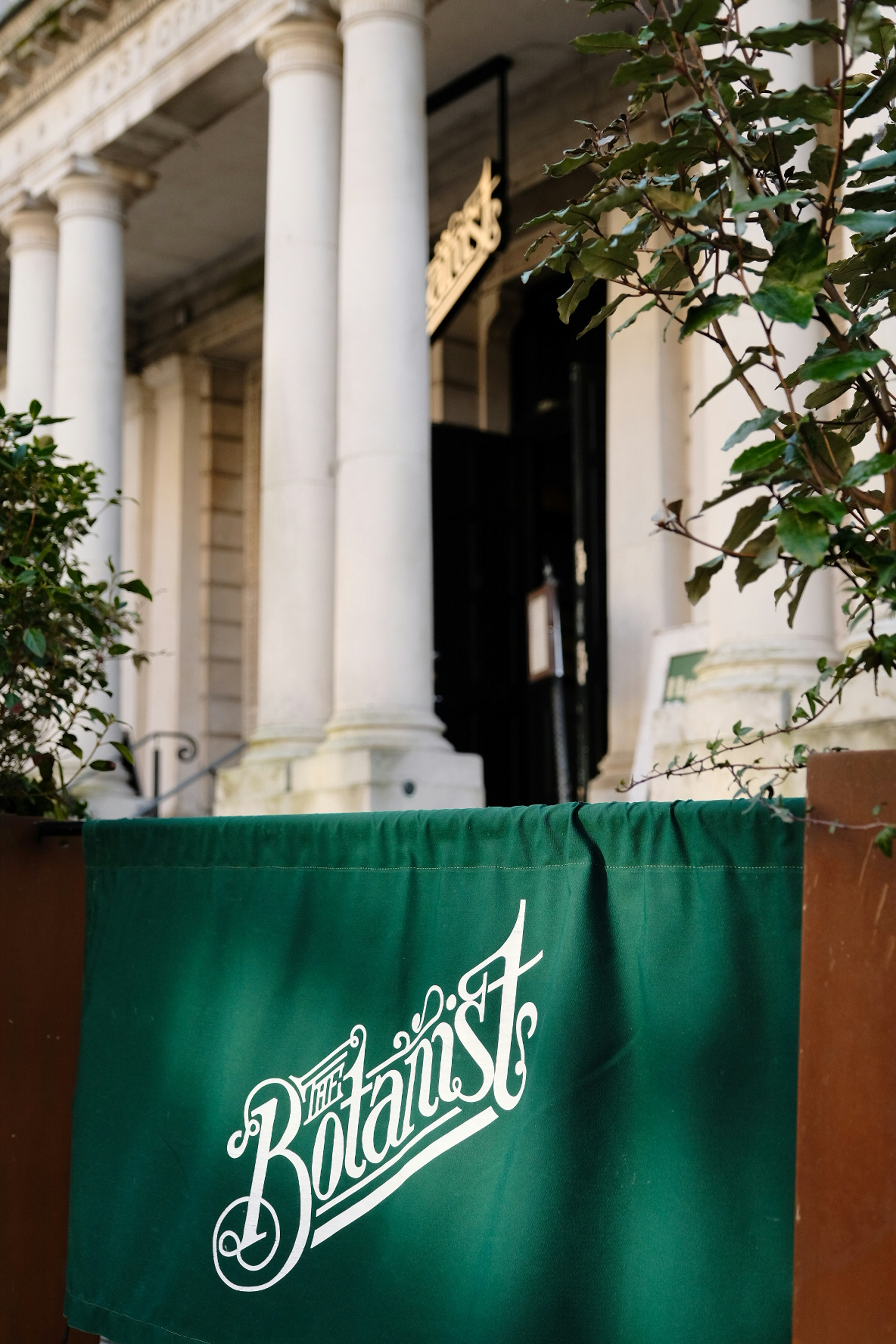 The Botanist Banner Framing a Stately Columned Entrance