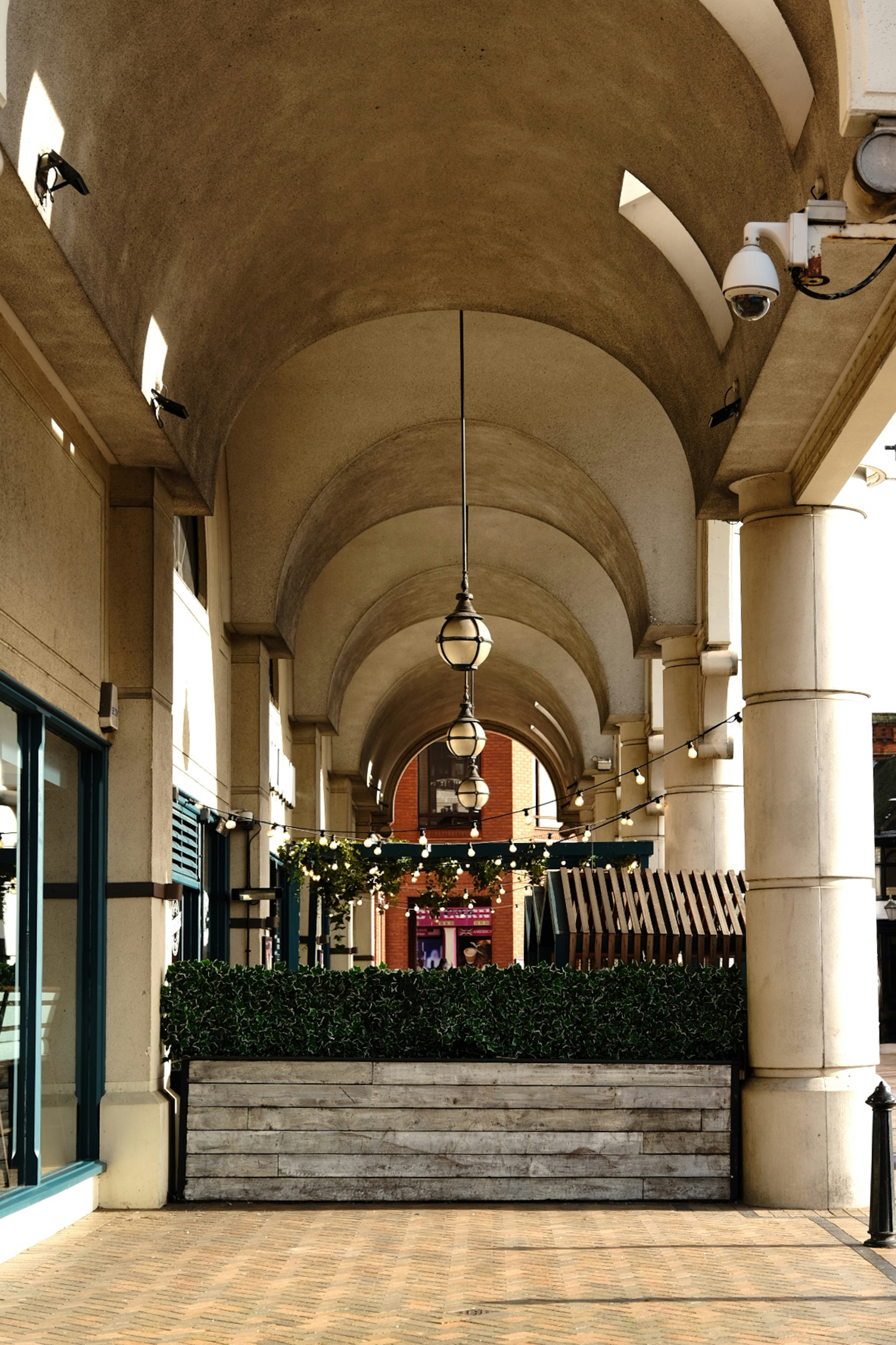 Arched Lantern Corridor: A Quiet, Sunlit Arcade Toward a Distant Atrium