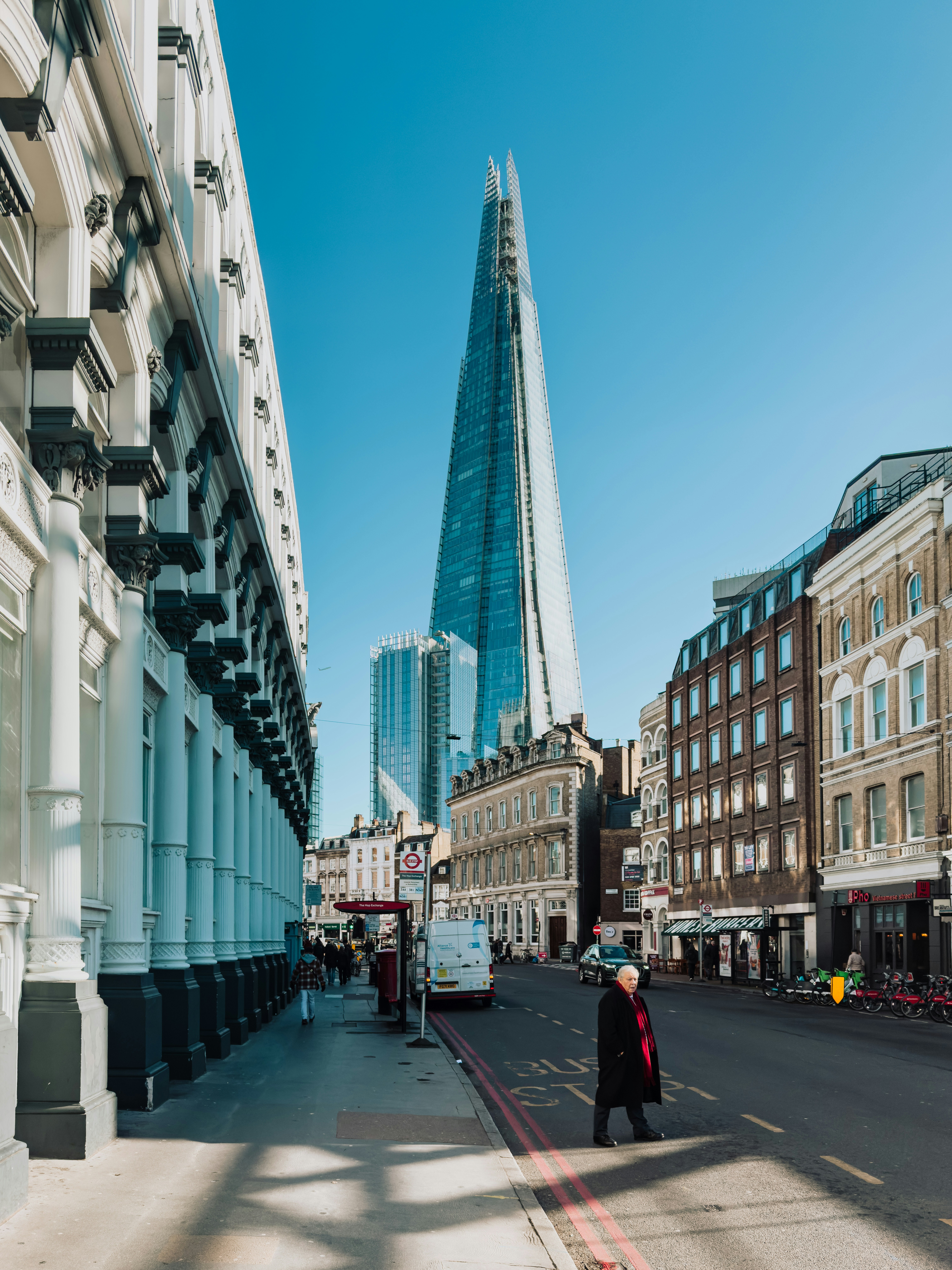 A woman walking down a street next to tall buildings