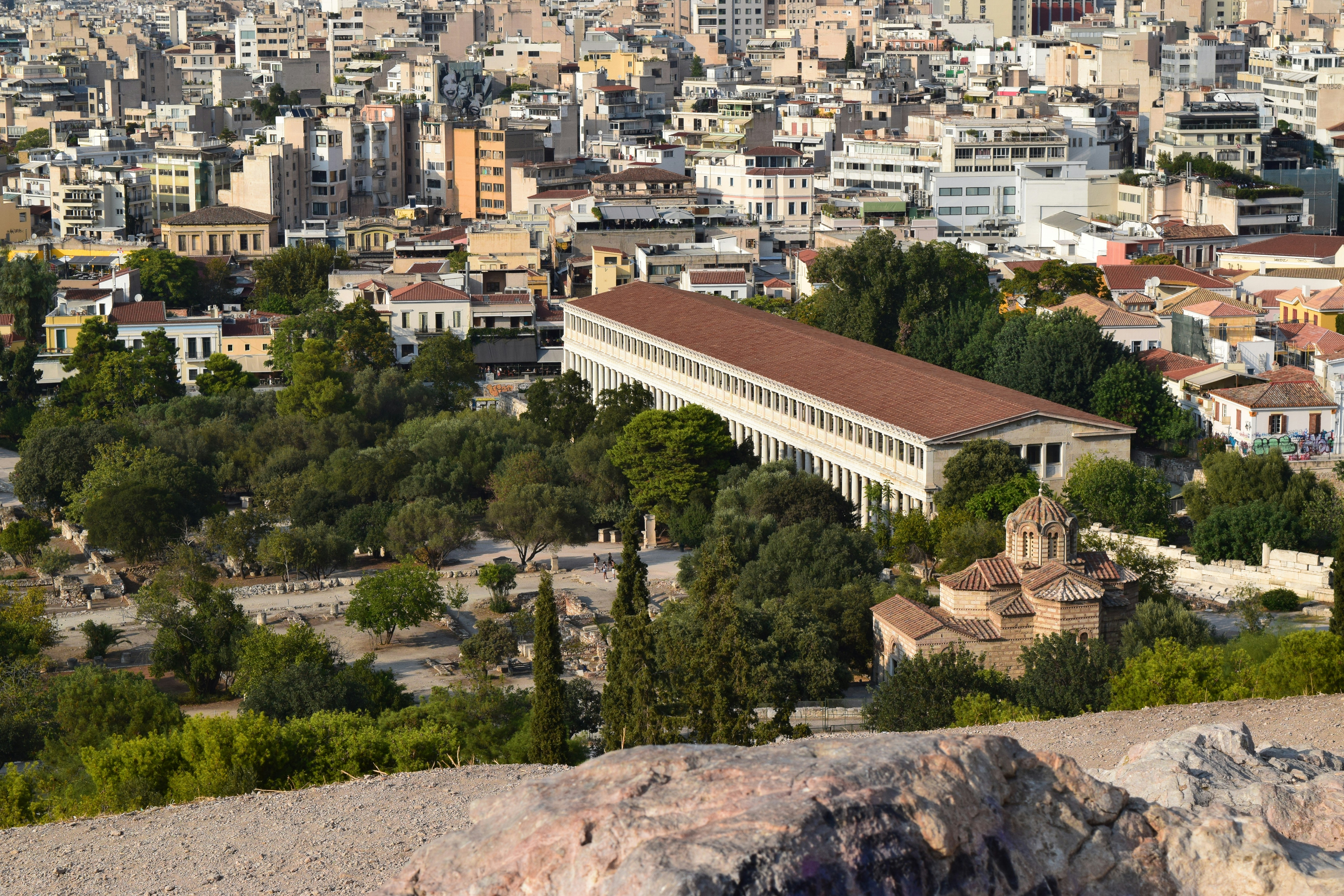 Ancient rock foreground overhanging a sunlit hillside cityscape
