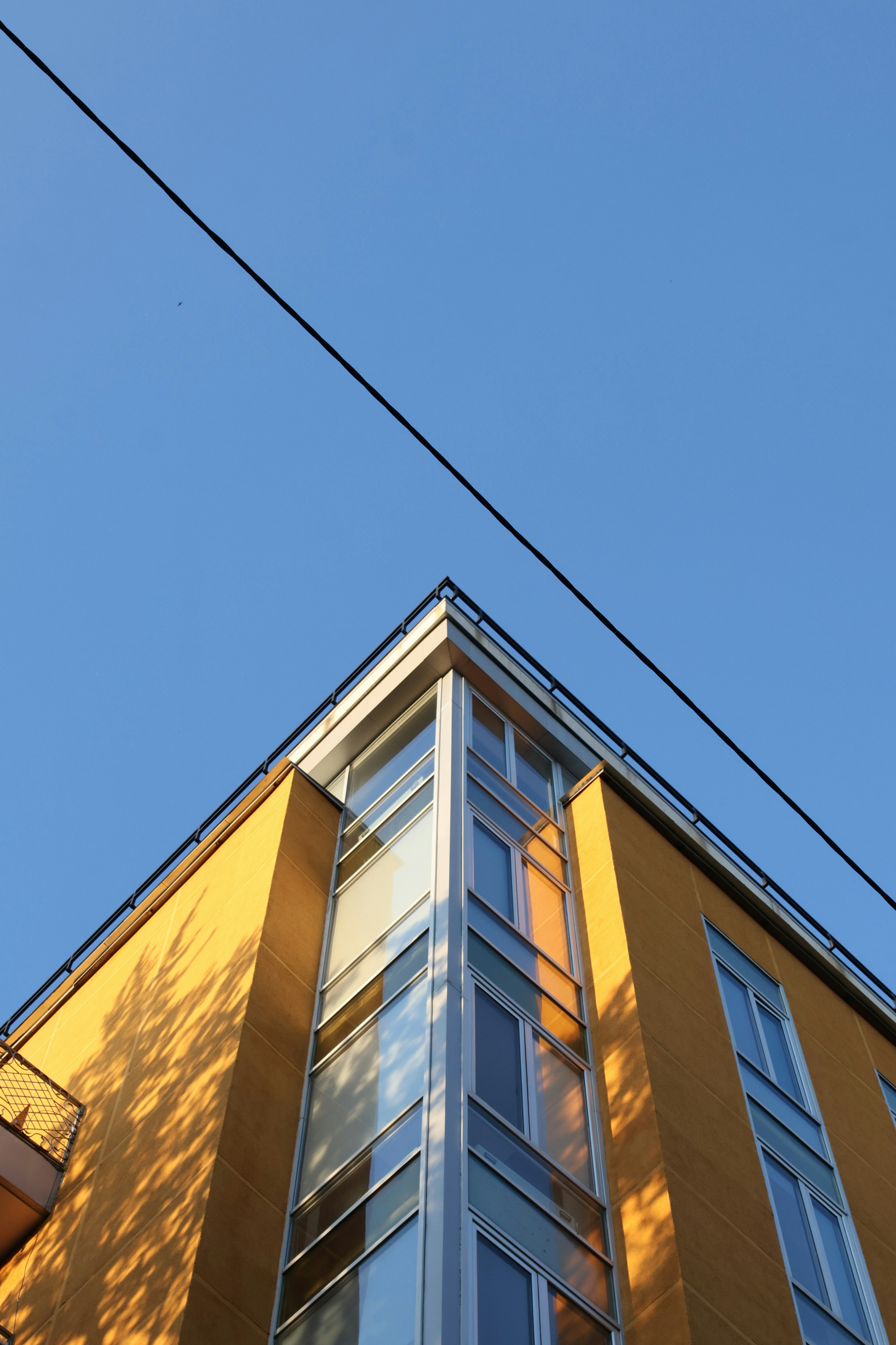 A tall yellow building with a blue sky in the background photo – Free ...