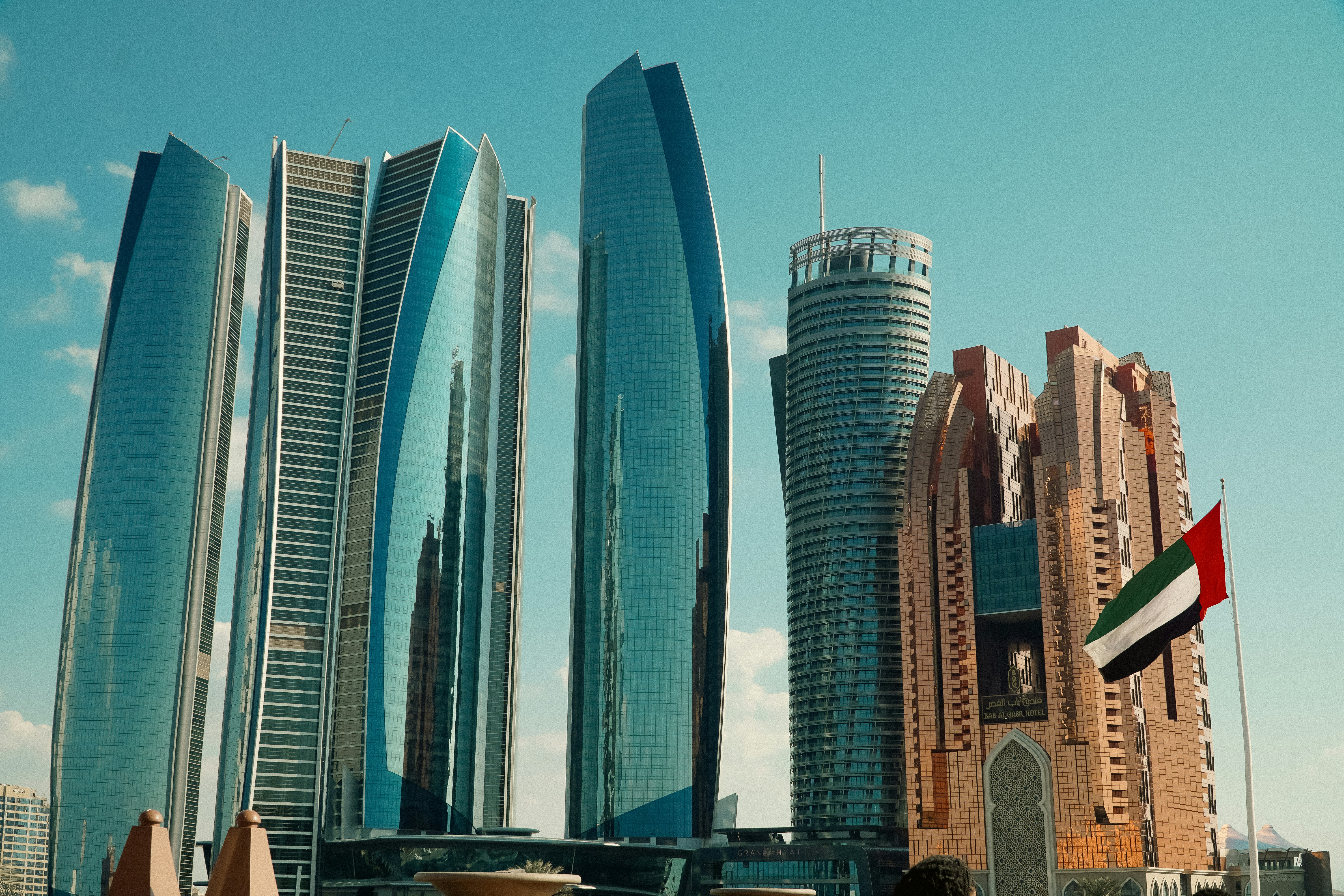 Cluster of glass skyscrapers with a clear sky backdrop, capturing architectural modernity and vibrant sunlight reflections.