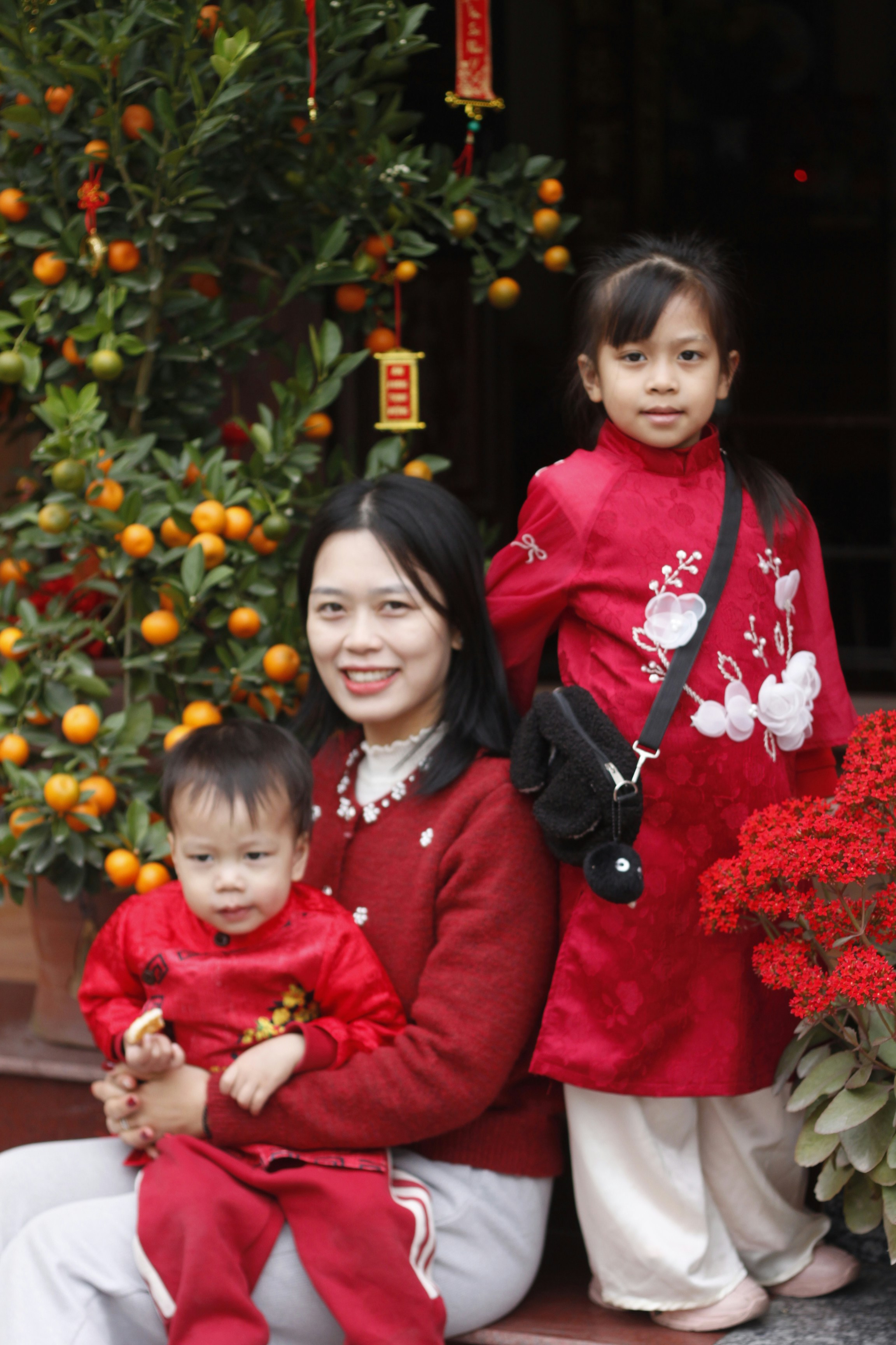 Warm Red harmony: Mother and daughters in a festive courtyard