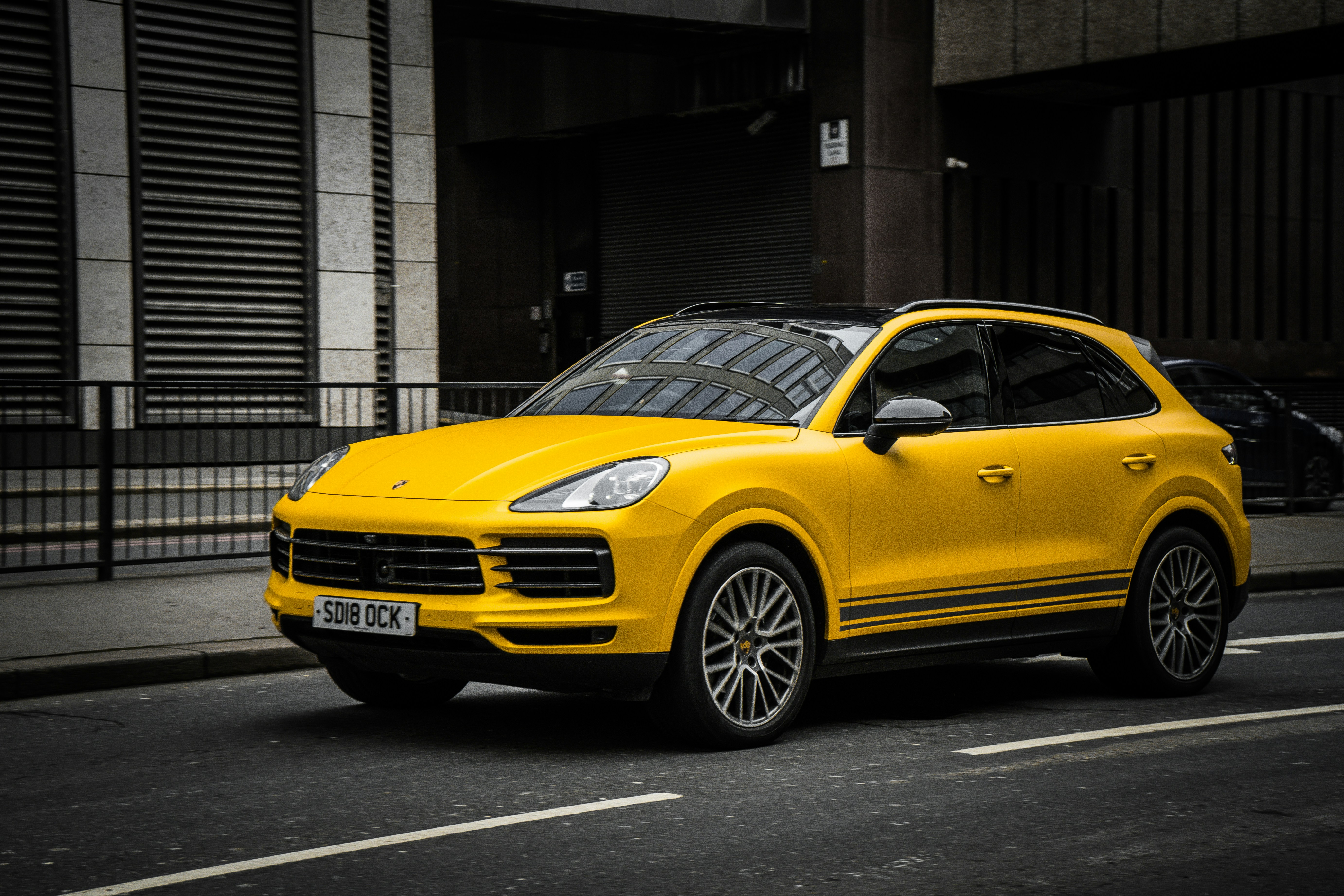 Bold yellow SUV cruising through a sleek urban landscape against modern architectural elements.