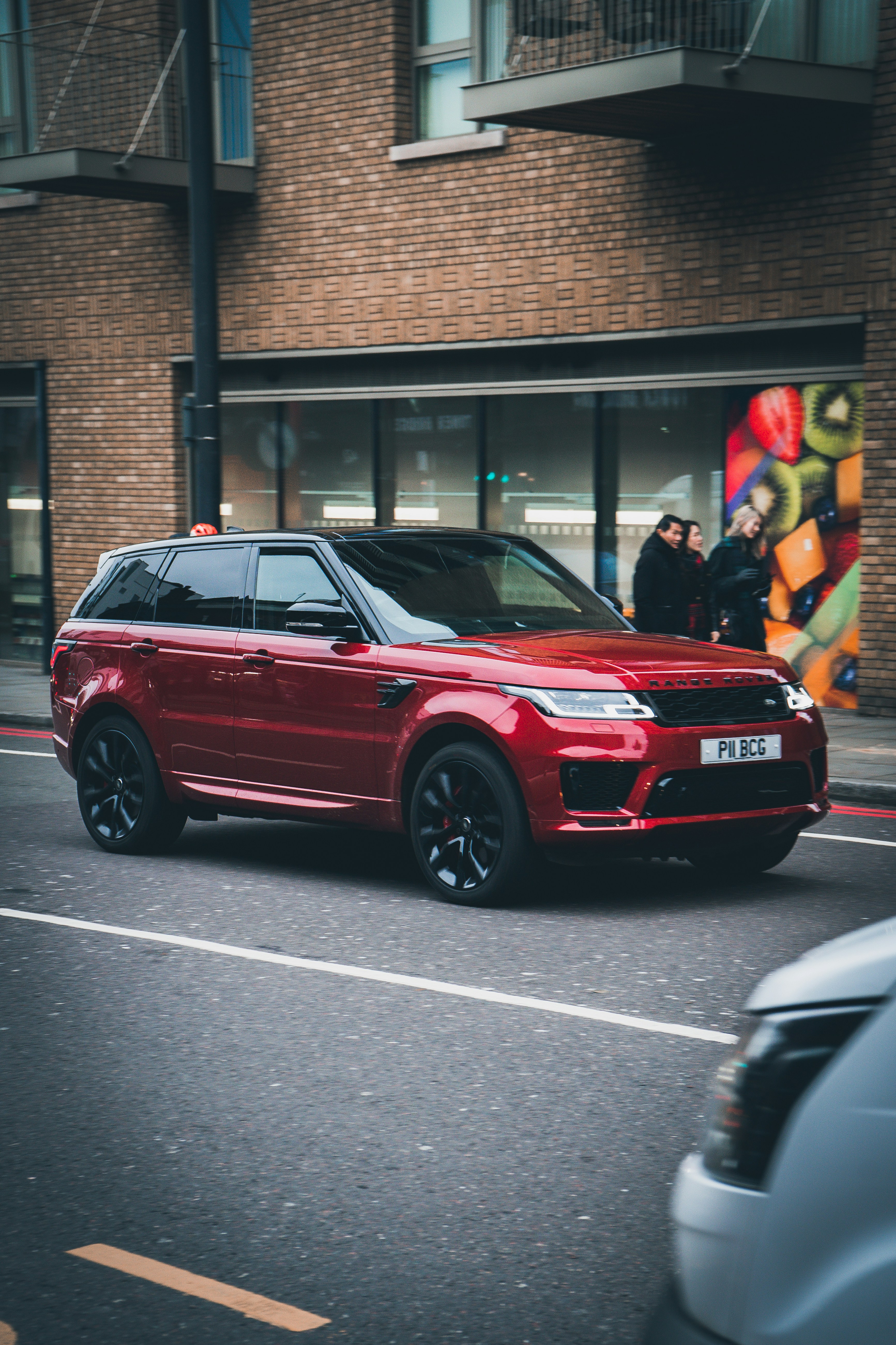 Crimson Range Rover at a City Block, Framed by Brick Facades and a Vivid Mural