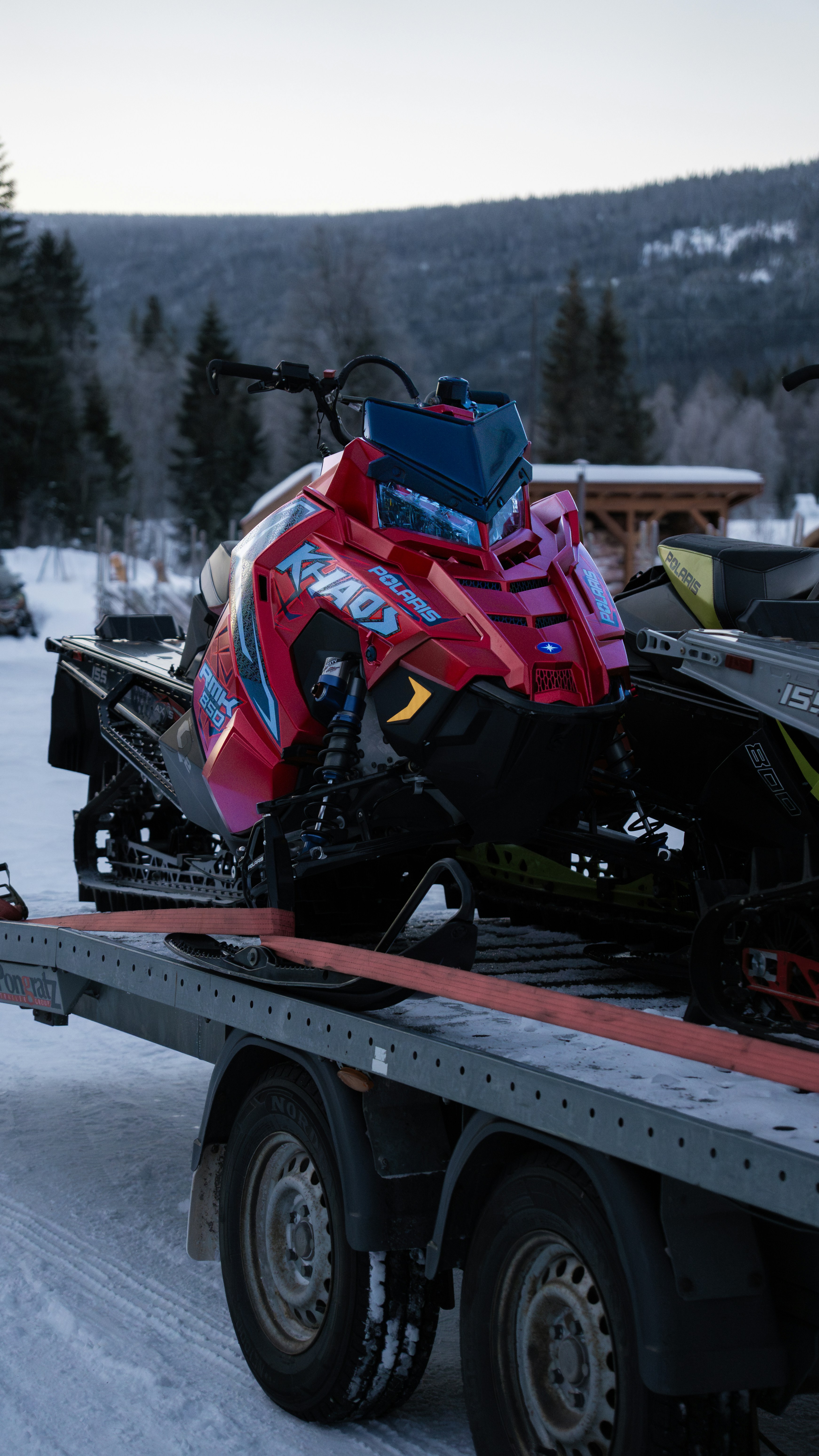 Crimson Snowmobile Locked on a Snow-Covered Trailer Under Alpine Light