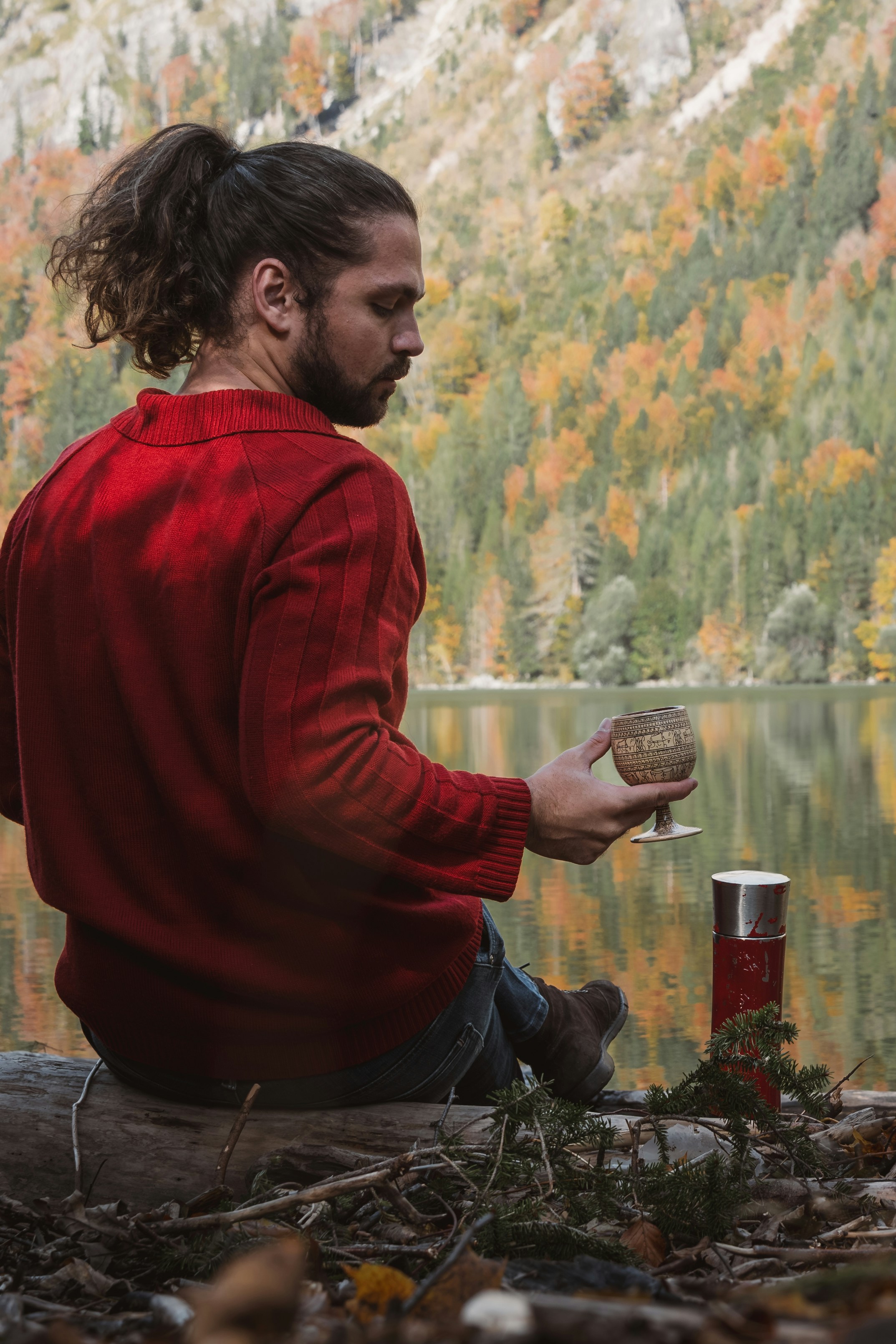 Red sweater, quiet moment: a solitary toast by the autumn lake