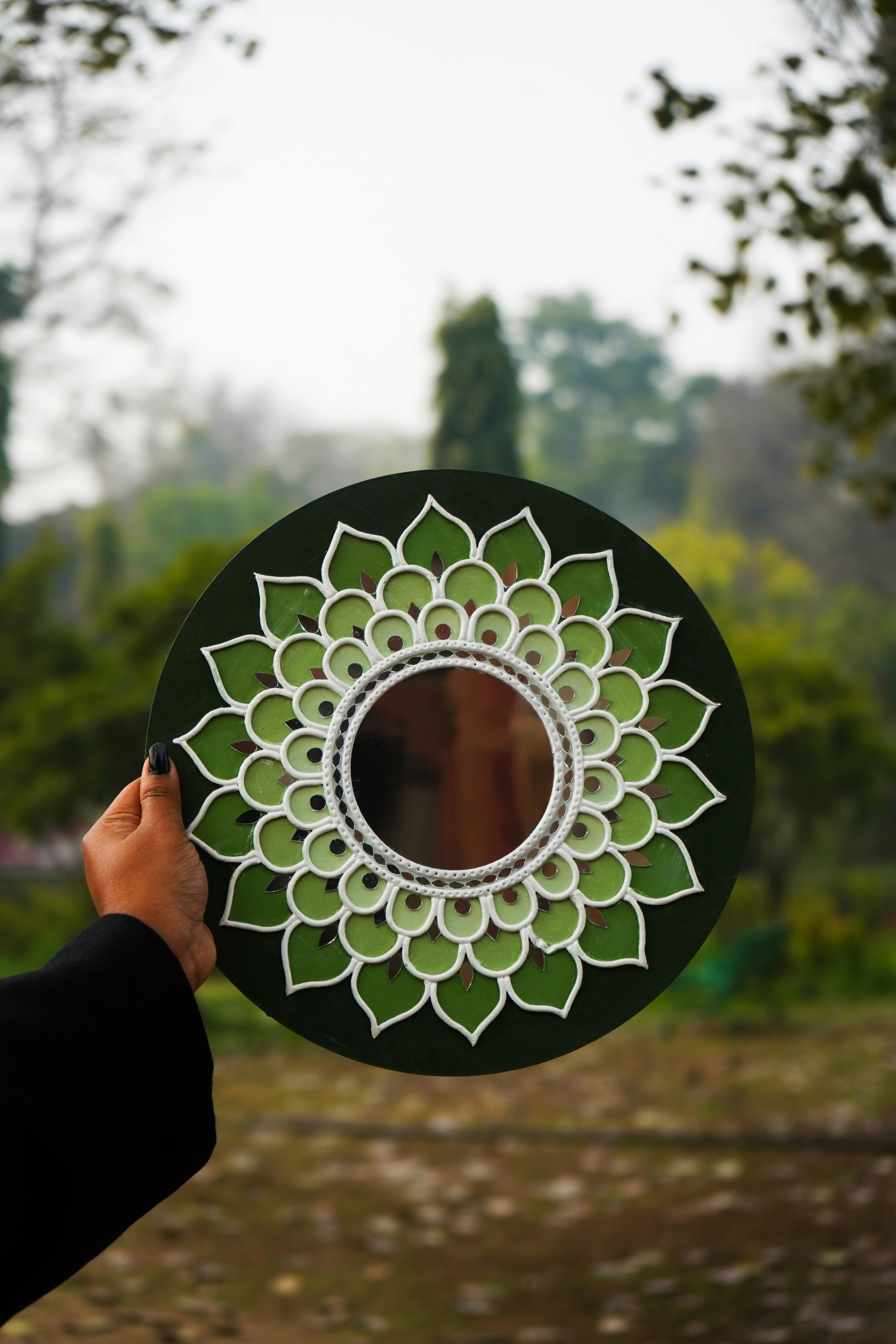 Hand-Held Green Mandala Mirror Turns a Garden Scene into a Quiet Reflection