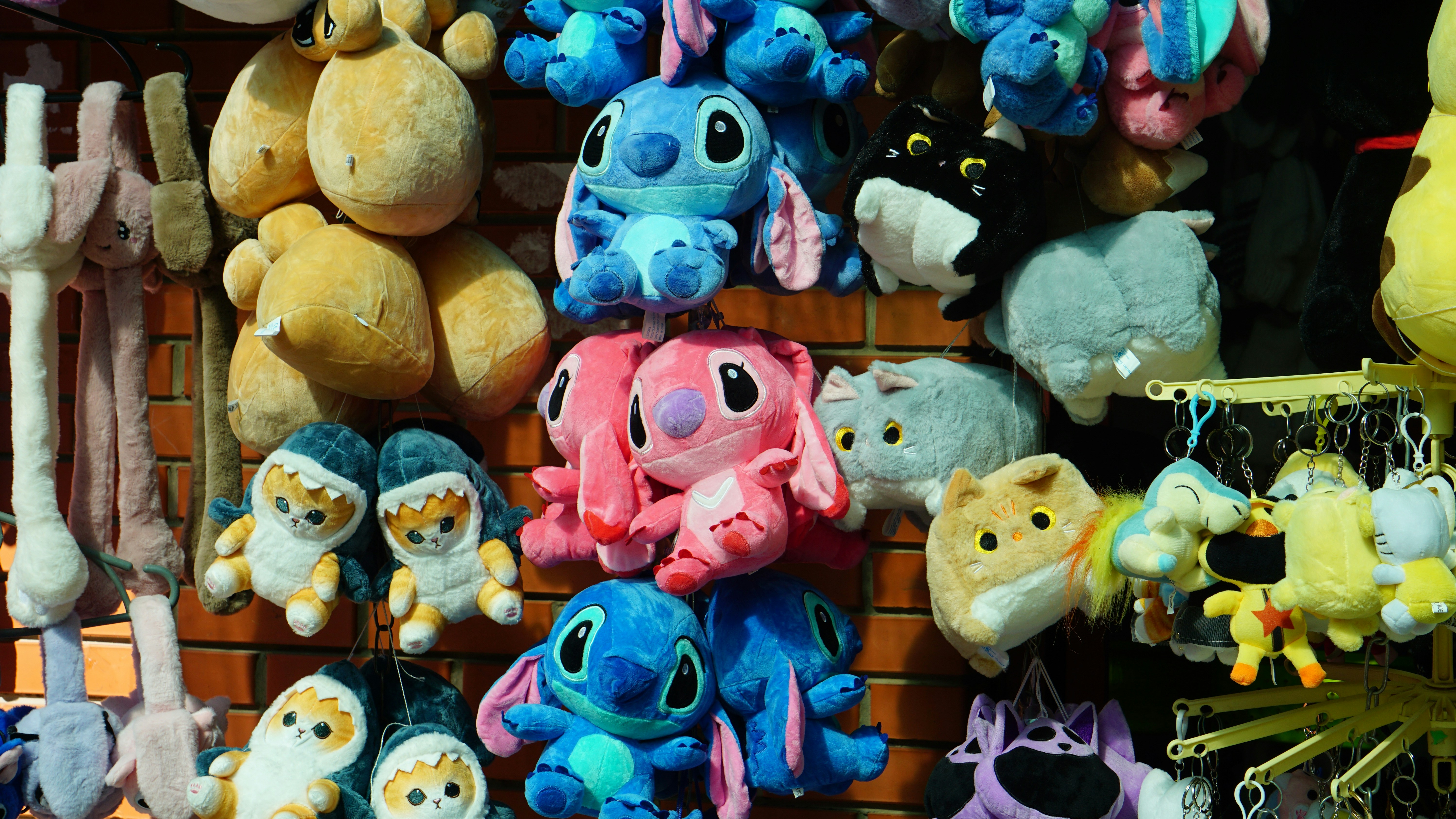 A vibrant display of assorted plush toys, featuring popular characters in various colors and designs, arranged against a textured backdrop.