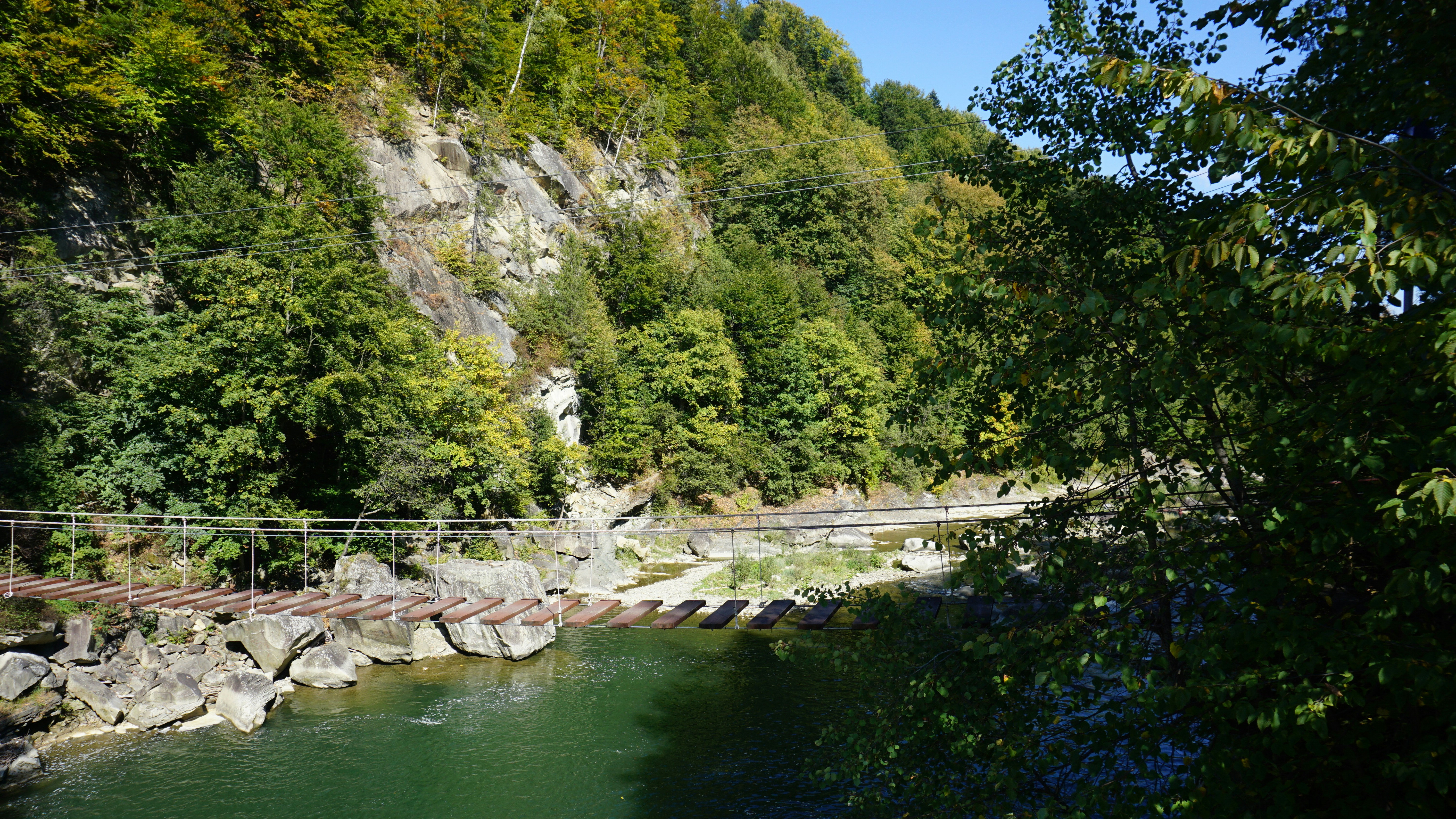 Verdant Gorge Crossing: Sunlit River Beneath a Rail Bridge
