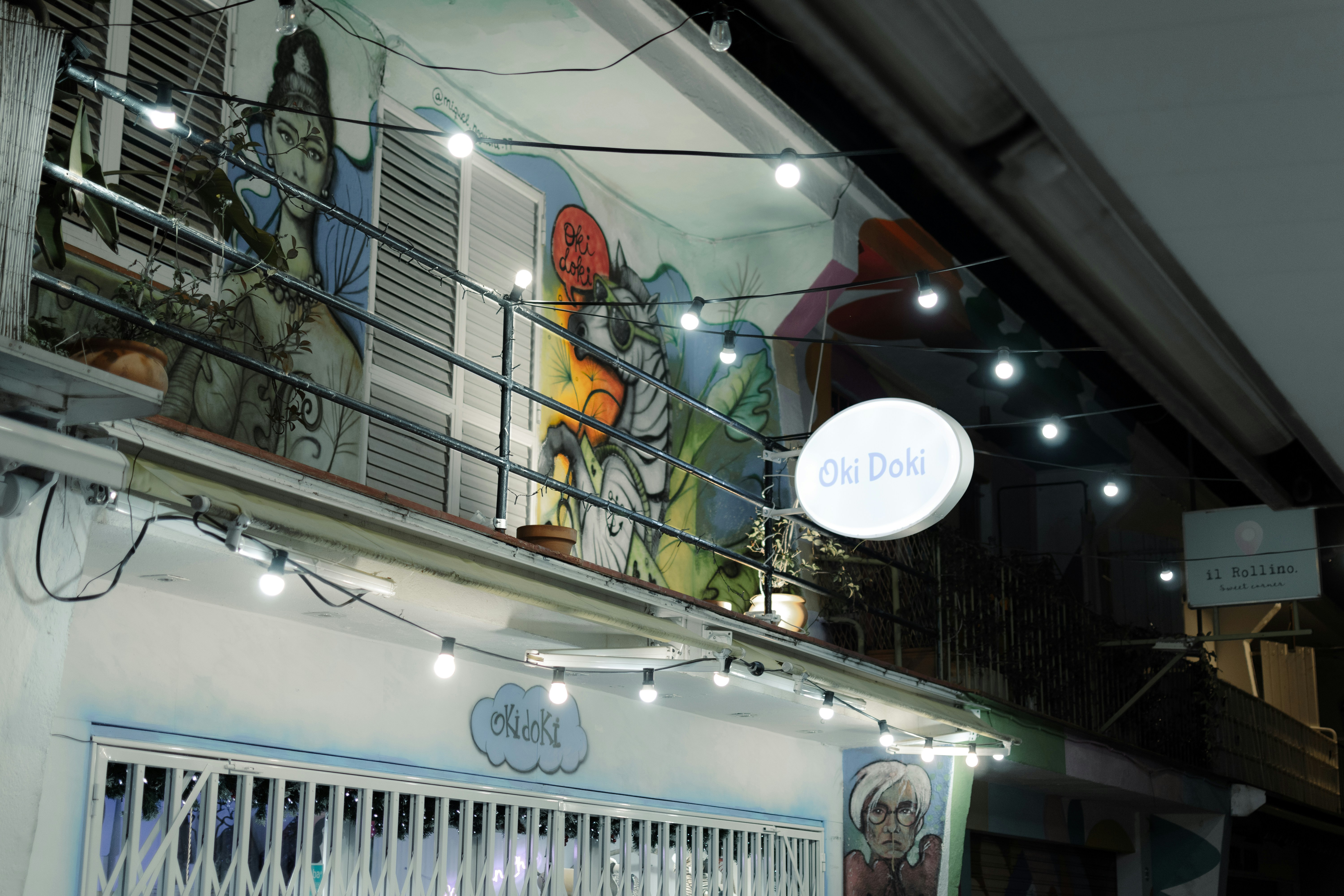 Colorful graffiti on a building facade lit by string lights, creating a vibrant urban atmosphere.