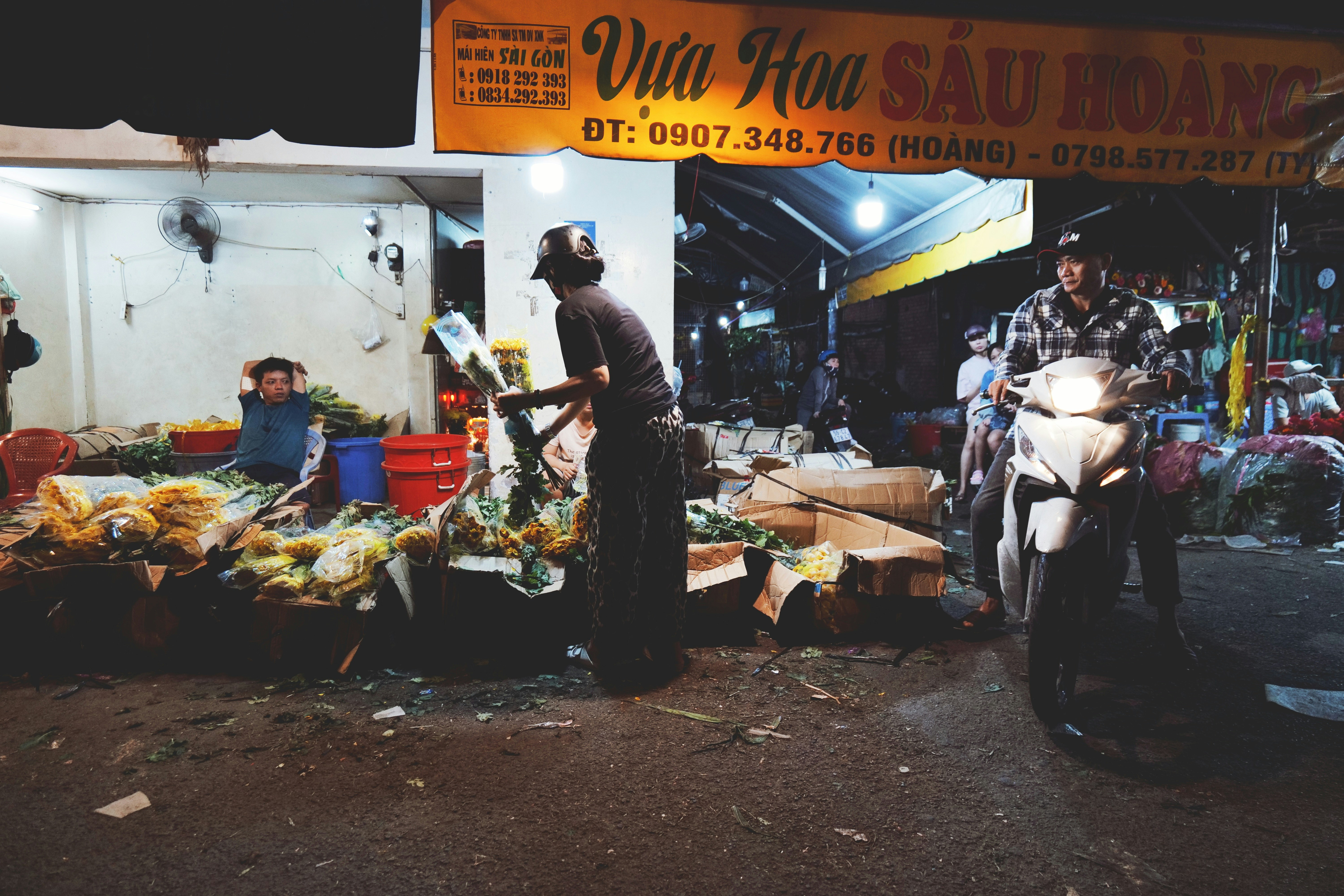 Market Night: A Vendor, Shopper, and Rider in a Hum of Street Corridor