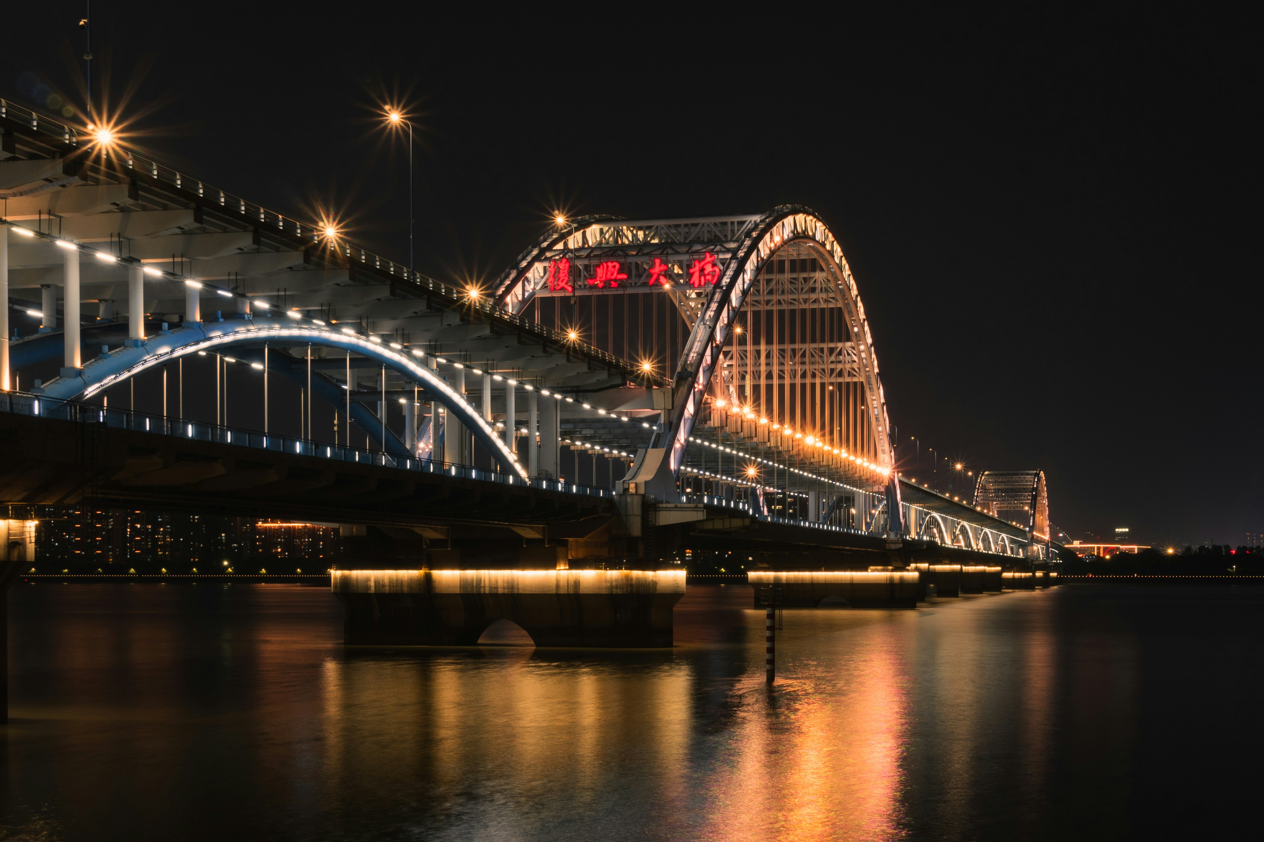 A large bridge over a body of water at night photo – Free Fuxing bridge ...
