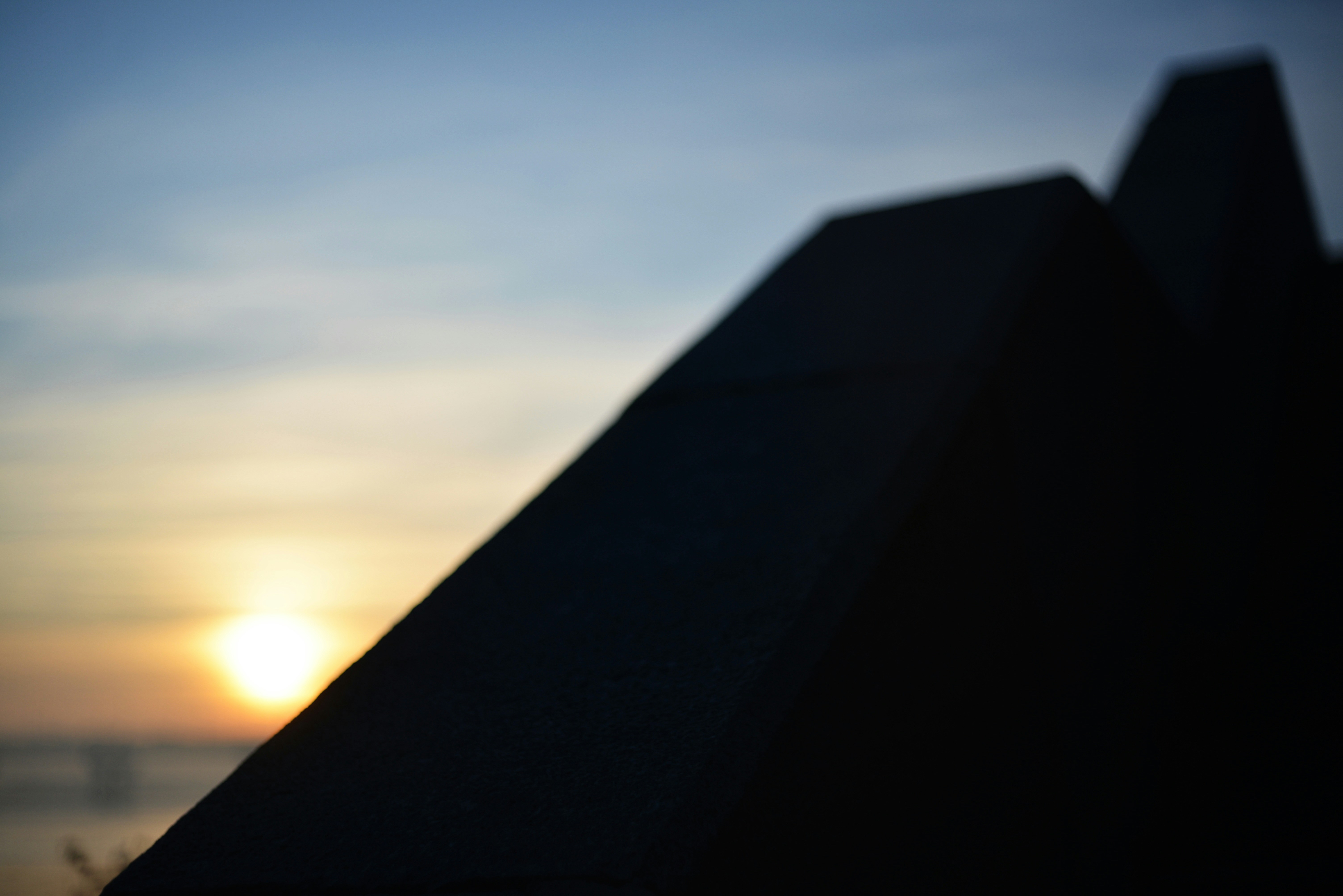 Shadowed angular structure contrasts with a gentle sunrise gradient.