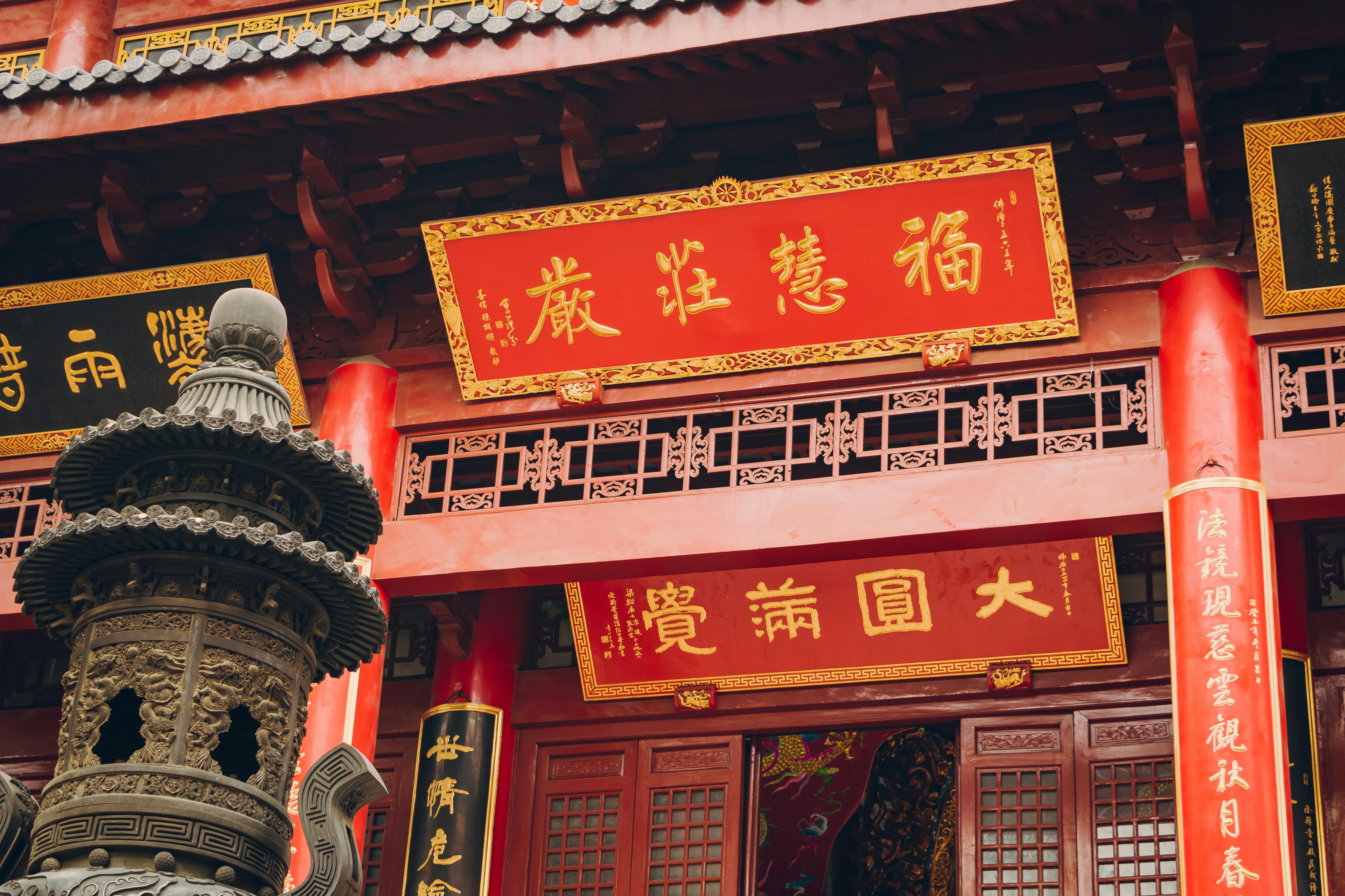 Traditional Chinese temple facade adorned with red and gold signs and intricate architectural details.
