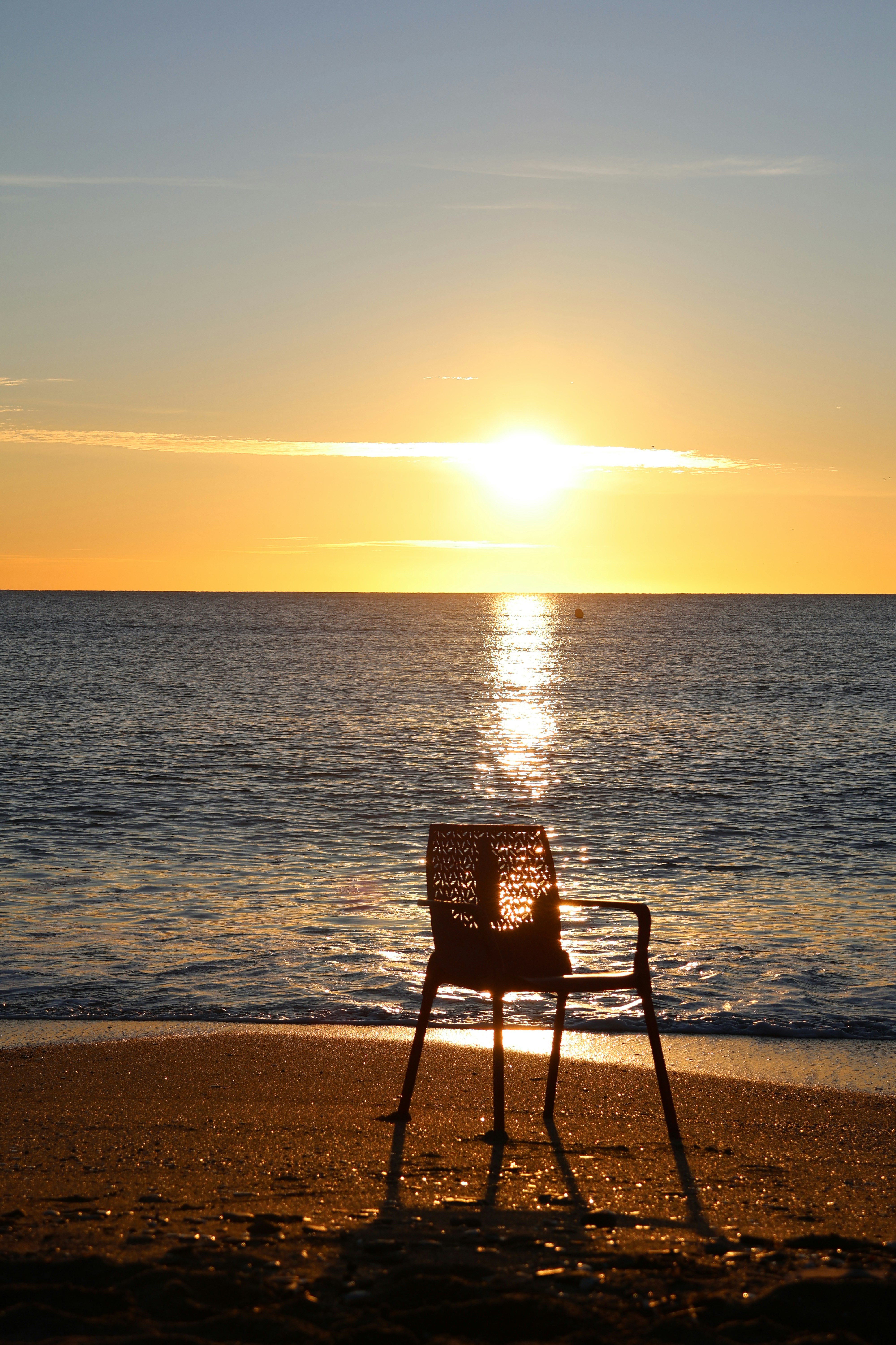 Solitary Sunset: A Woven Chair Silhouette on a Quiet Beach