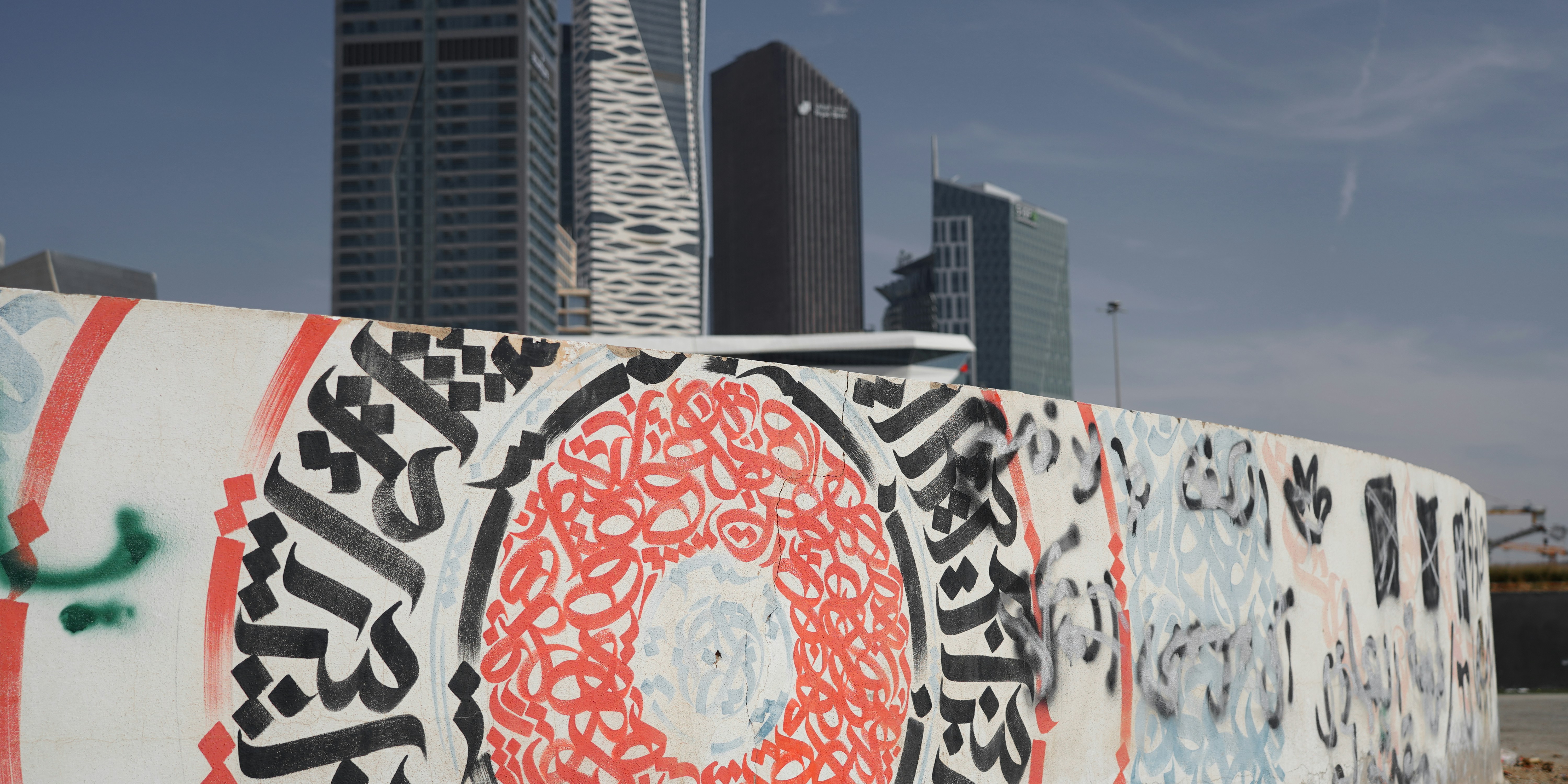 Colorful graffiti with intricate patterns contrasts against modern skyscrapers under a clear sky.