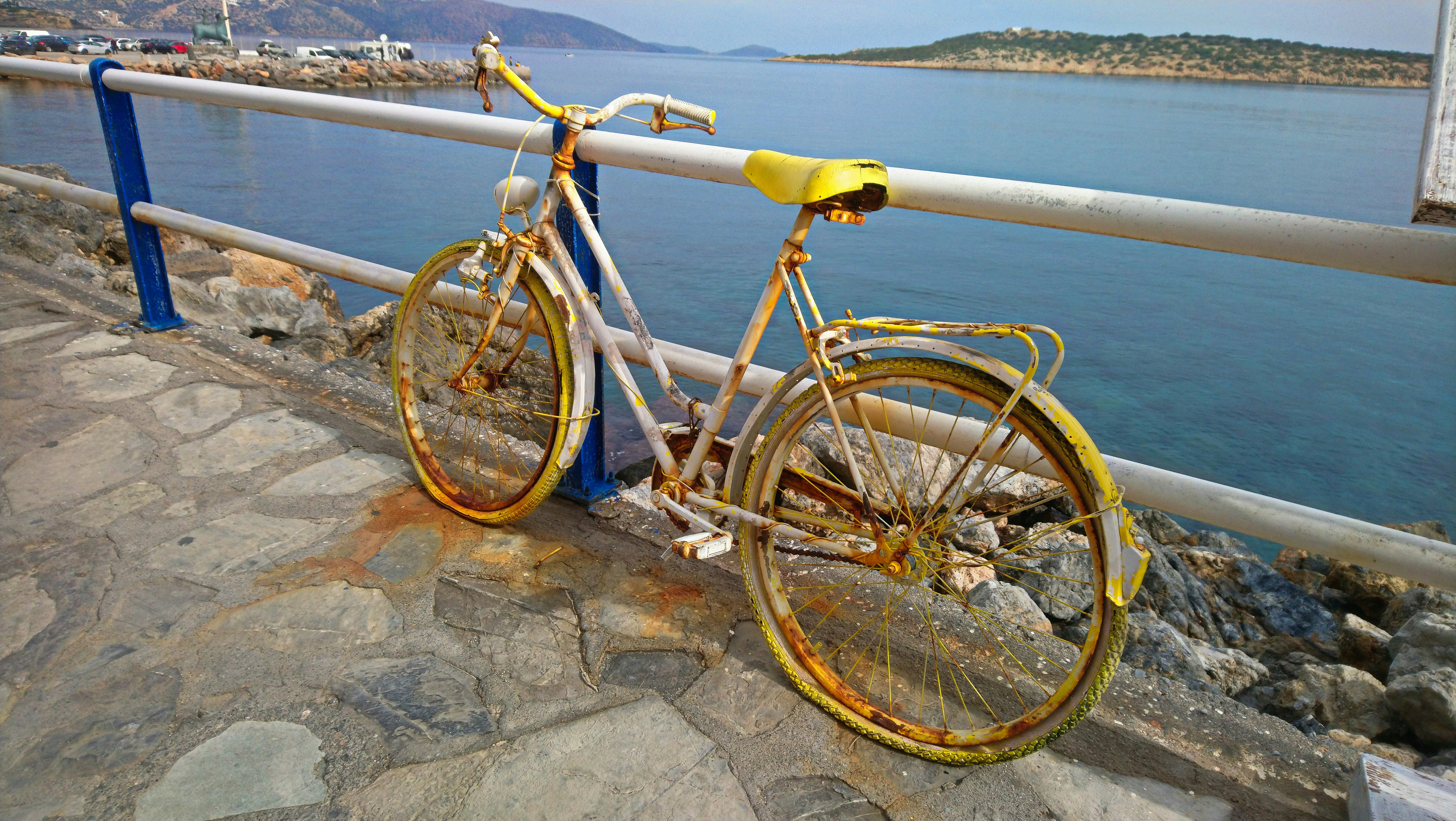 A yellow bicycle parked next to a railing near the ocean