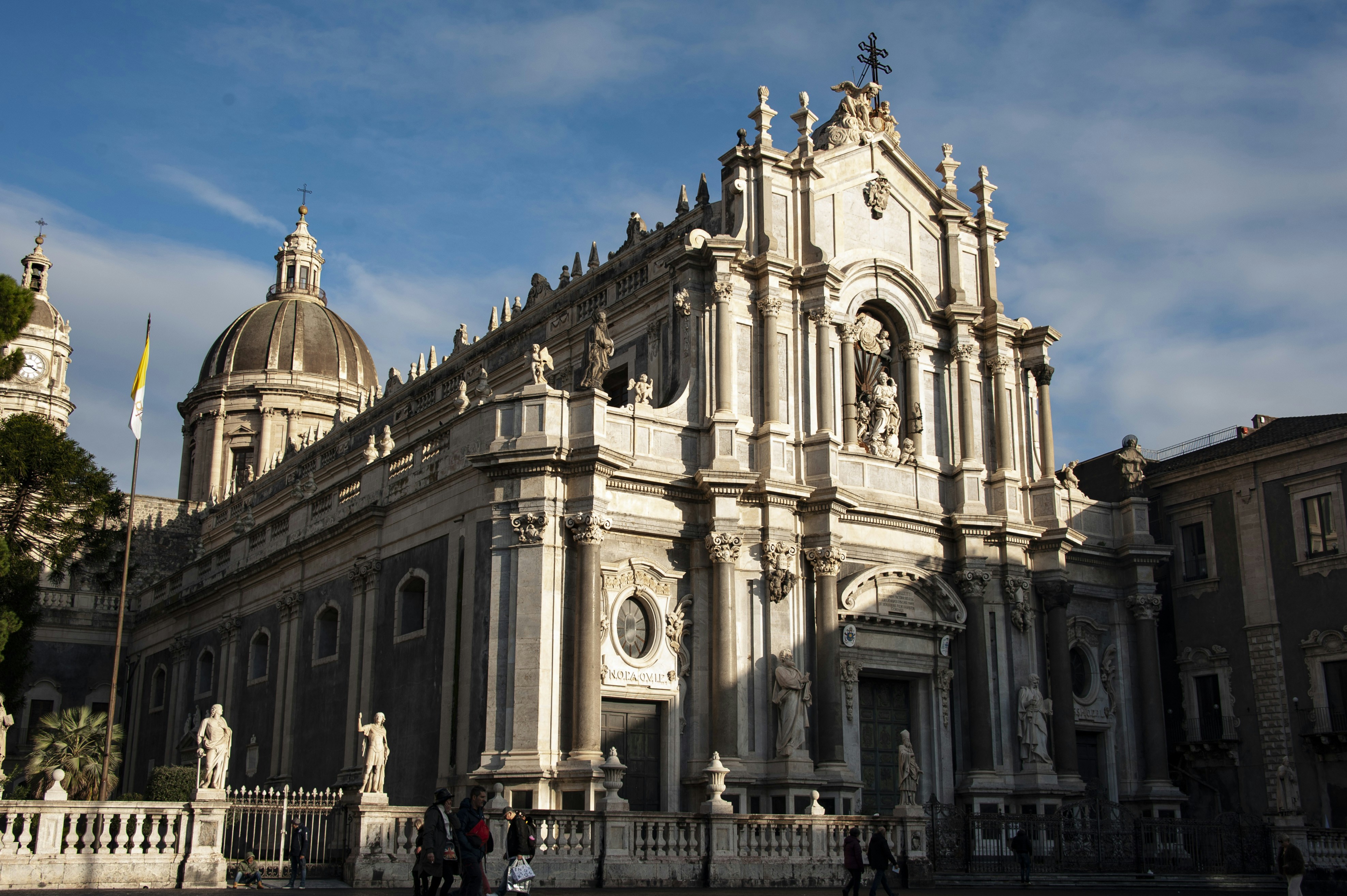 Grand cathedral with intricate stone facade illuminated by warm sunlight against a deep blue sky.