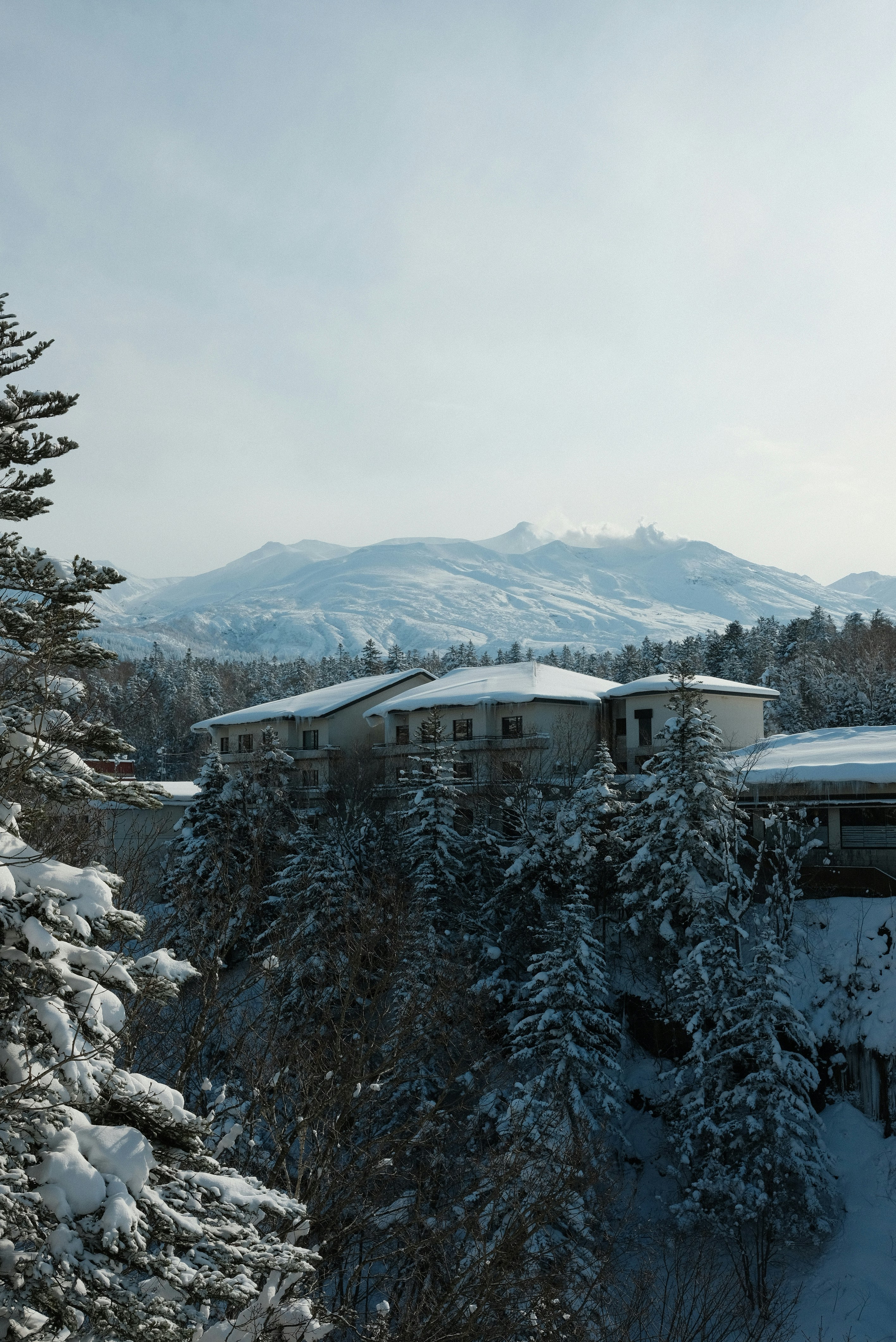 A snow covered mountain with a building in the foreground