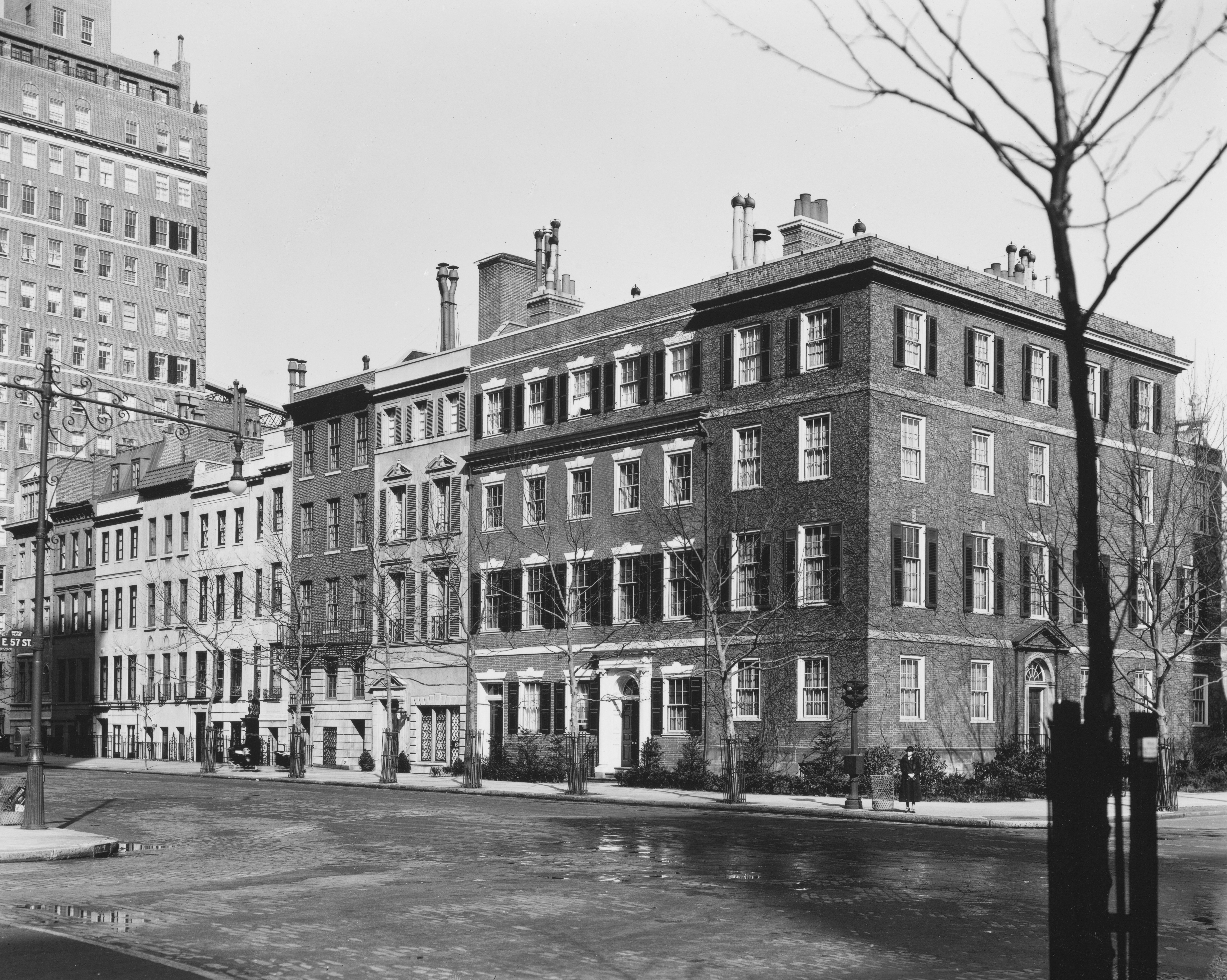 Intricate brick buildings line a quiet urban street, captured in soft daylight with gentle shadows emphasizing architectural details.