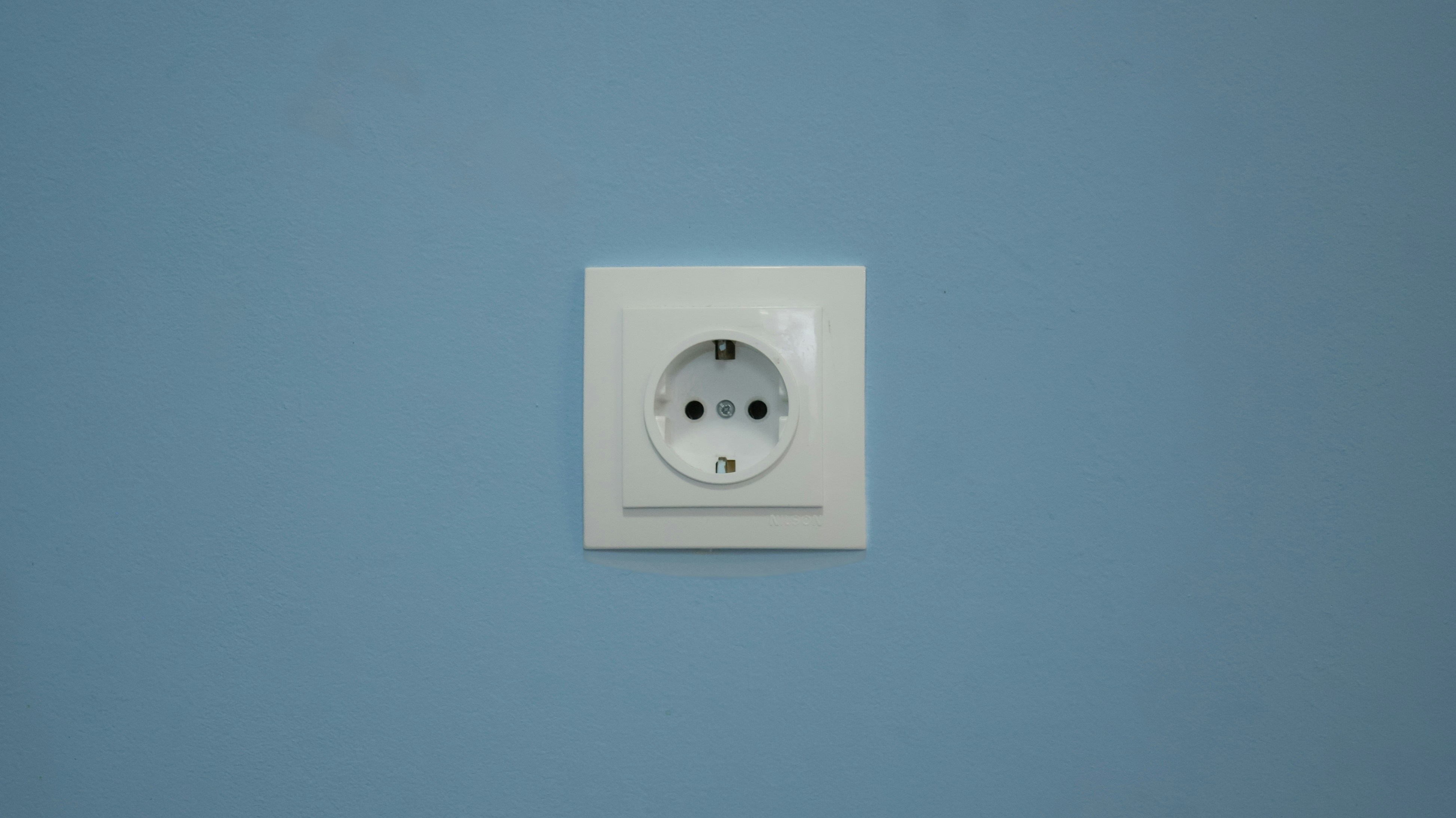 White electrical outlet set against a tranquil blue wall with soft lighting accentuating the minimalist design.
