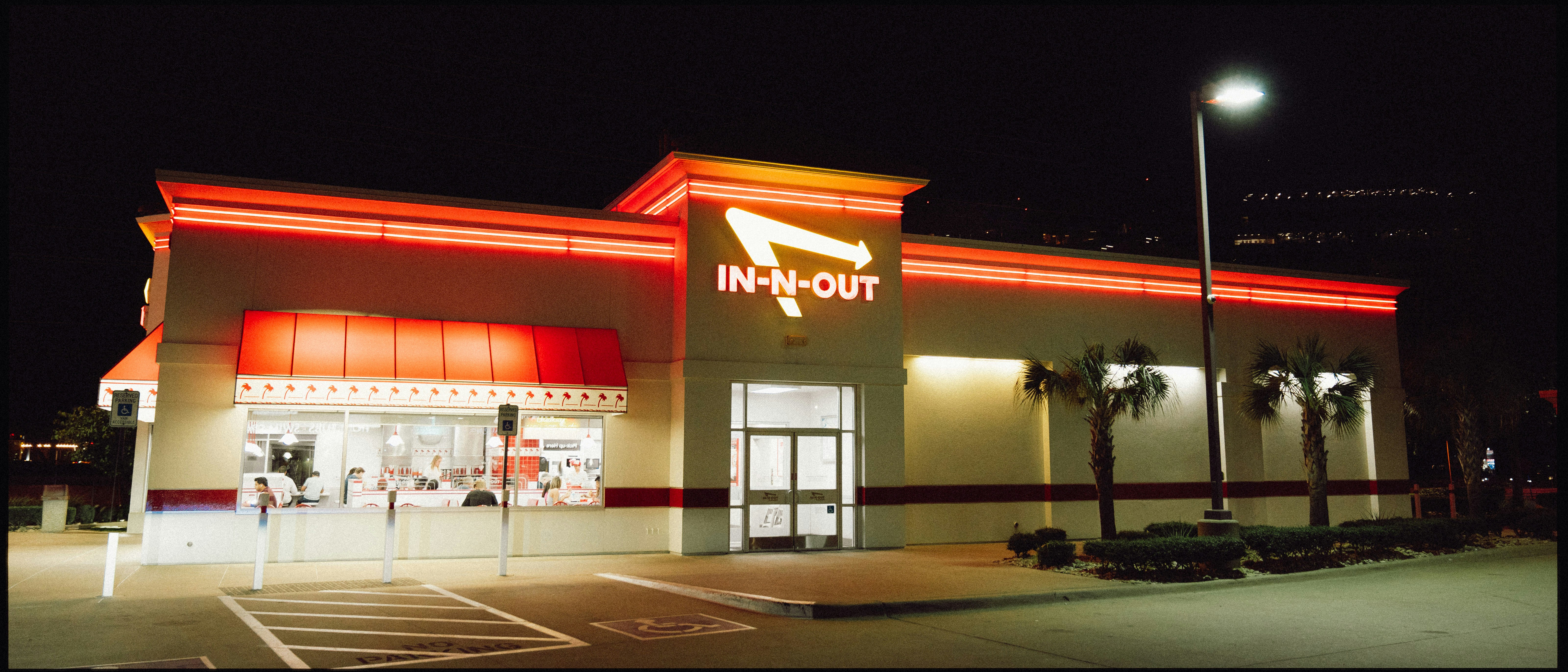 Fast-food restaurant illuminated with neon lights at night.