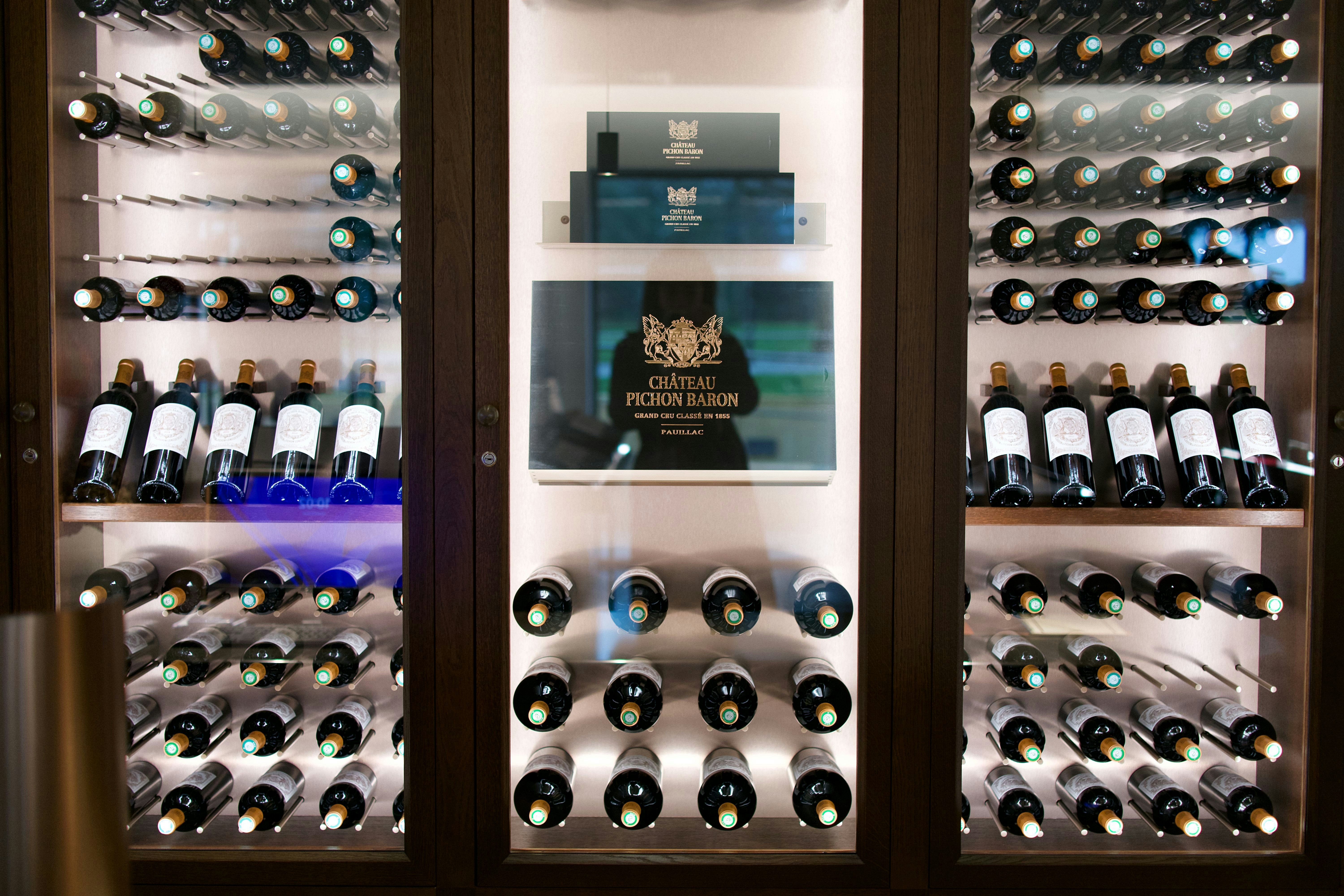 Illuminated wine display featuring rows of elegantly arranged bottles in a glass cabinet.