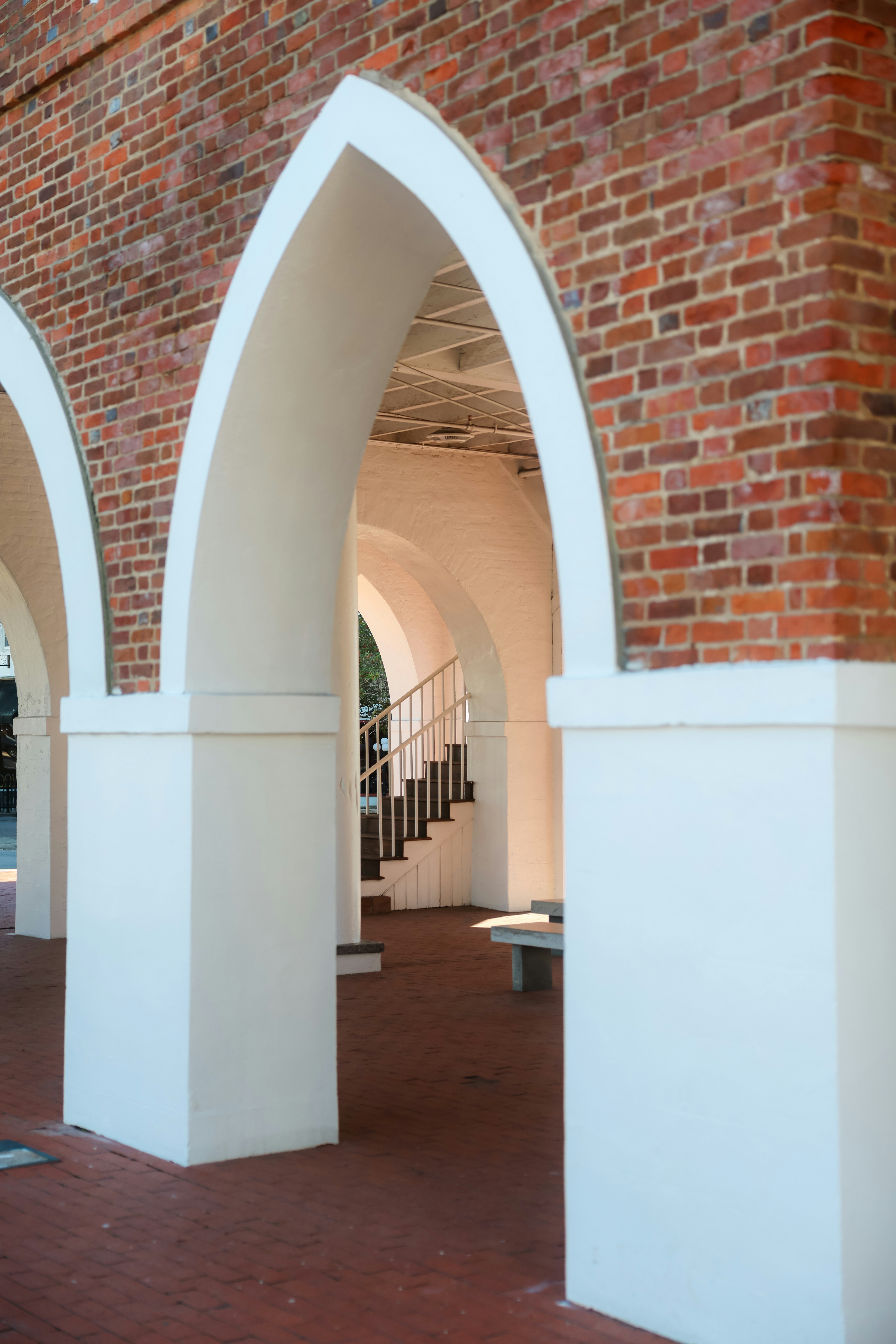 A brick building with arches and benches on the side of it photo – Free ...