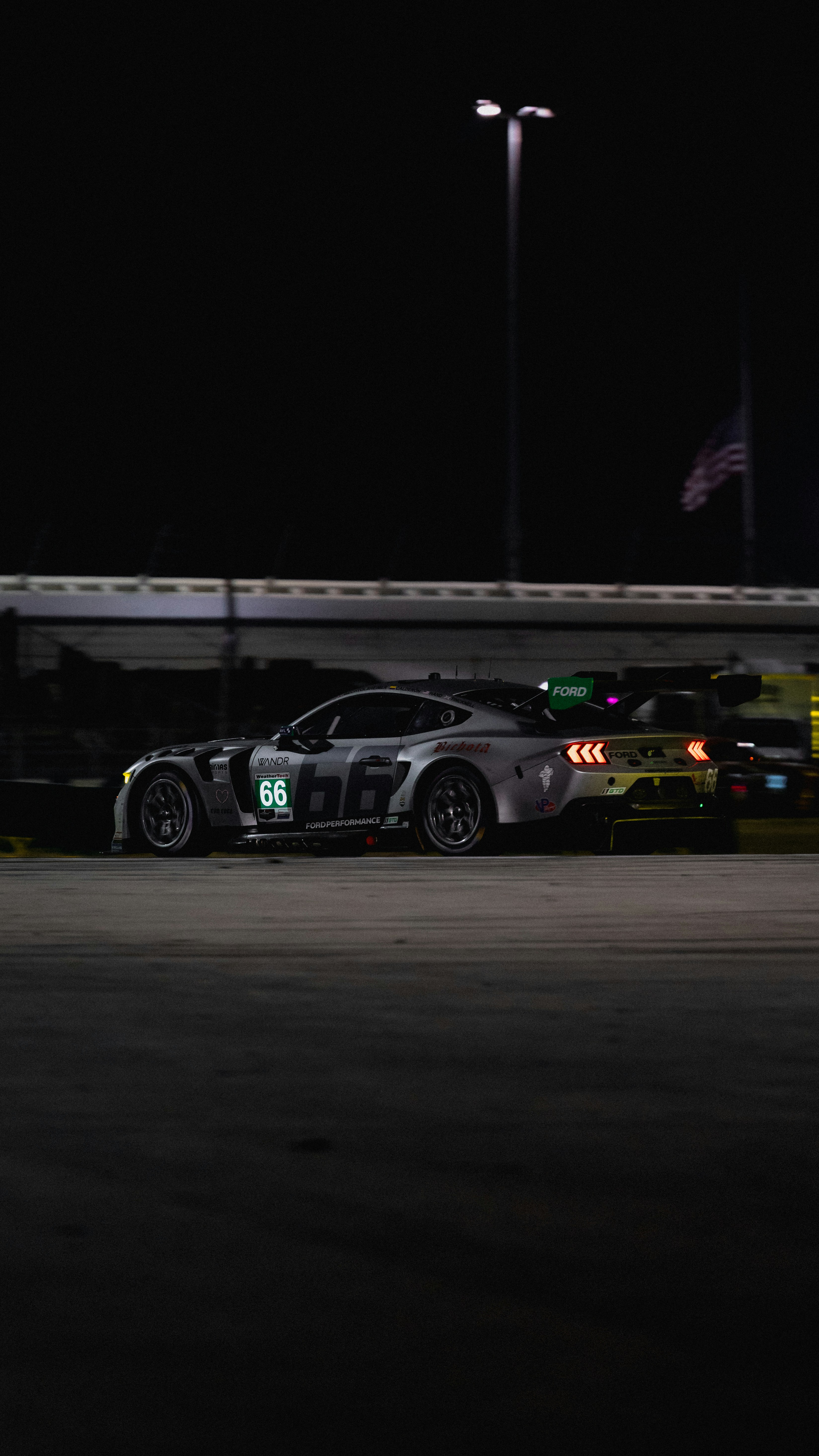 Night Race silhouette: a silver GT car blooms under stadium lights