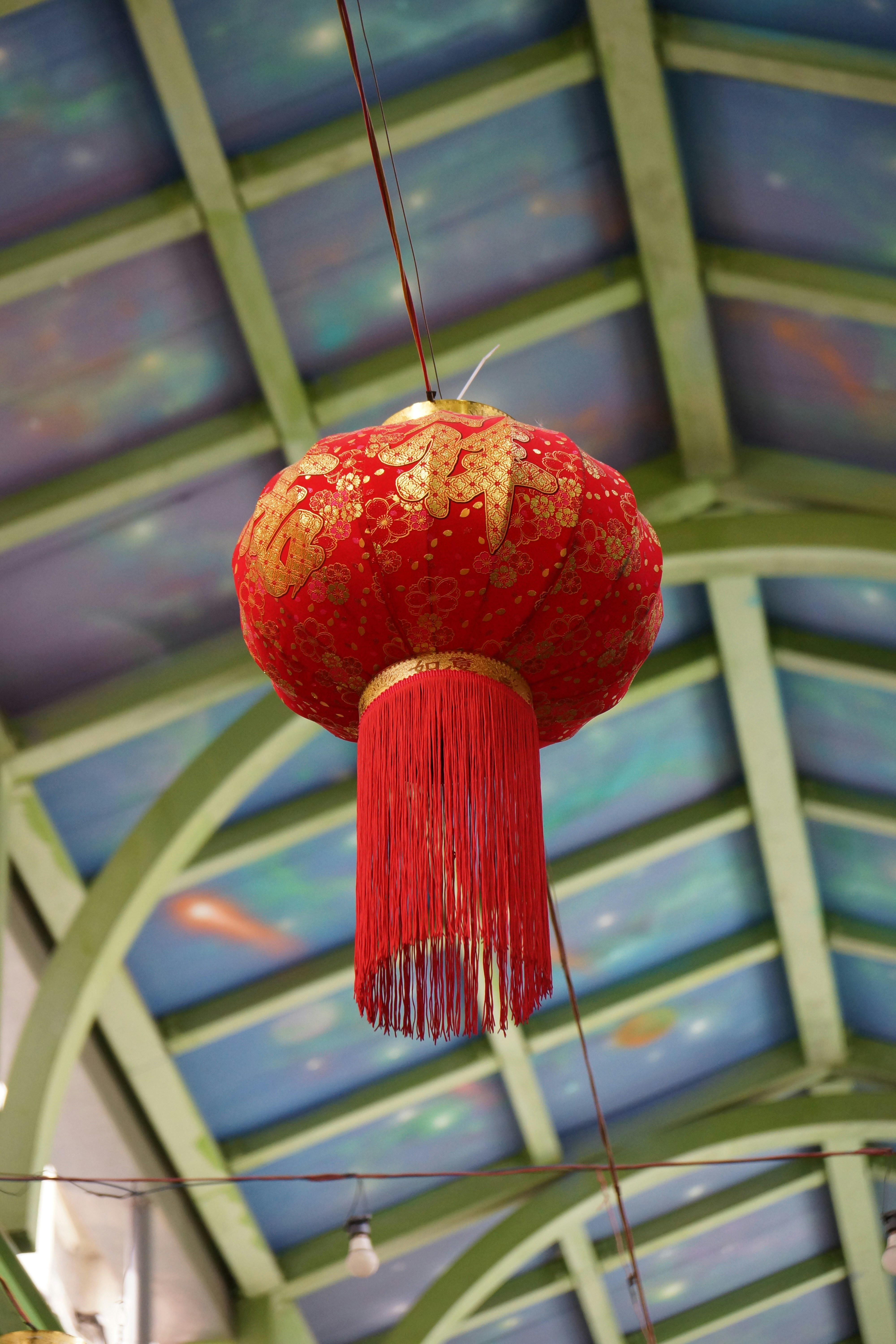 A red lantern hanging from a ceiling in a building photo – Free Red ...