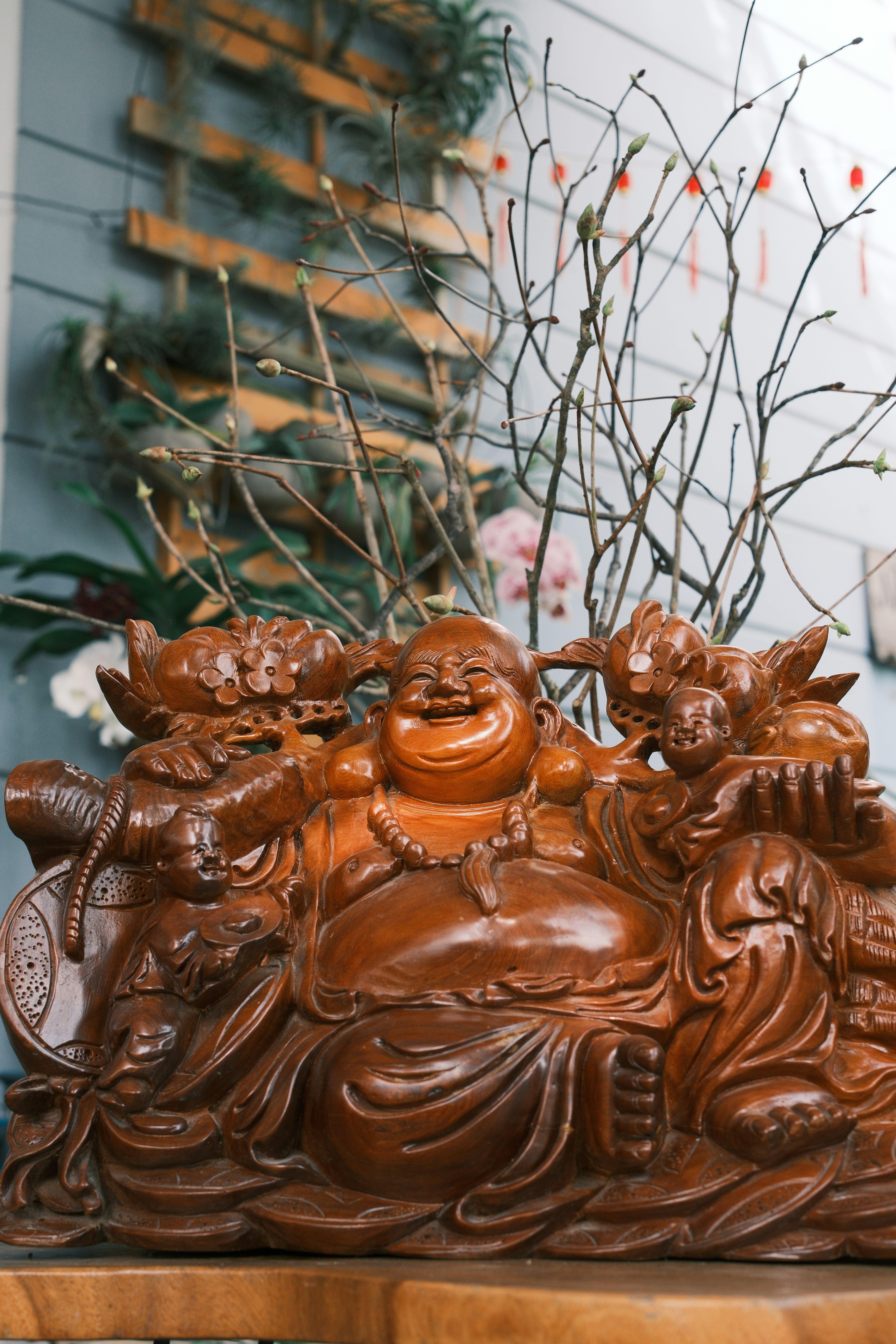 Amber-Hued Laughing Buddha: a Wood Carving Anchored by Bare Branches