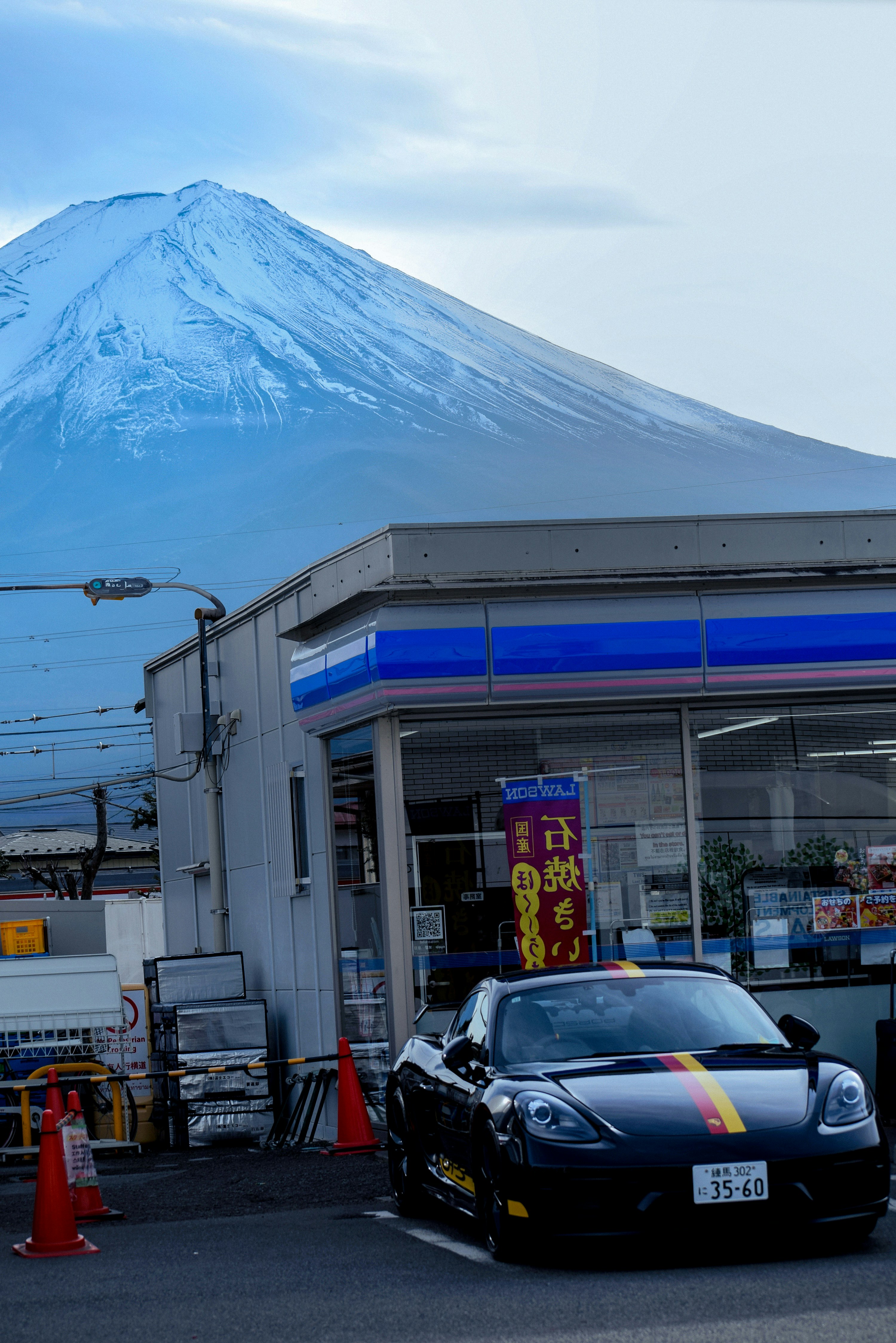 Mt. Fuji backdrop over a neon-striped convenience store and parked sports car