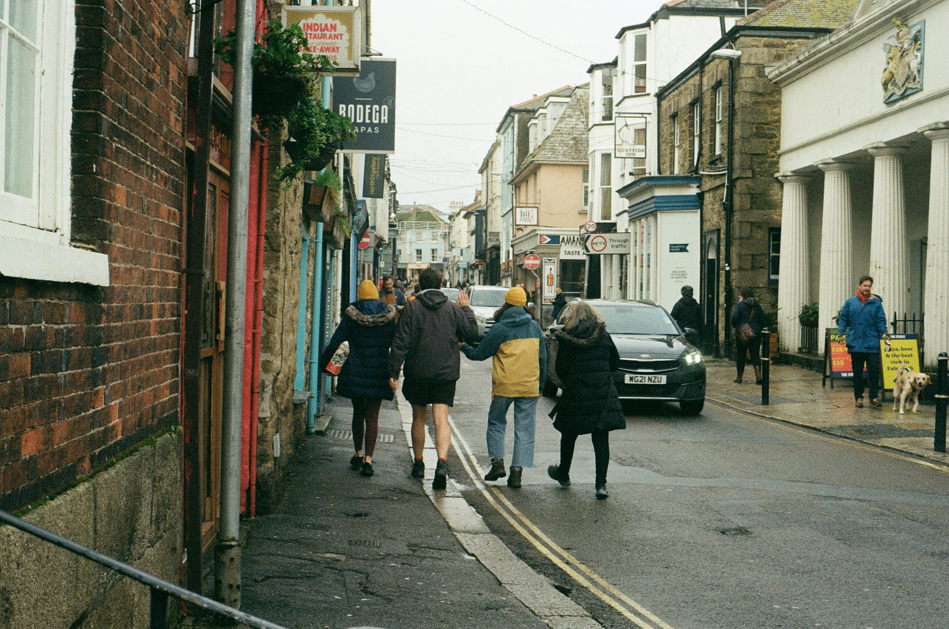 Group of people walking down a narrow, cobblestone street lined with historic buildings.