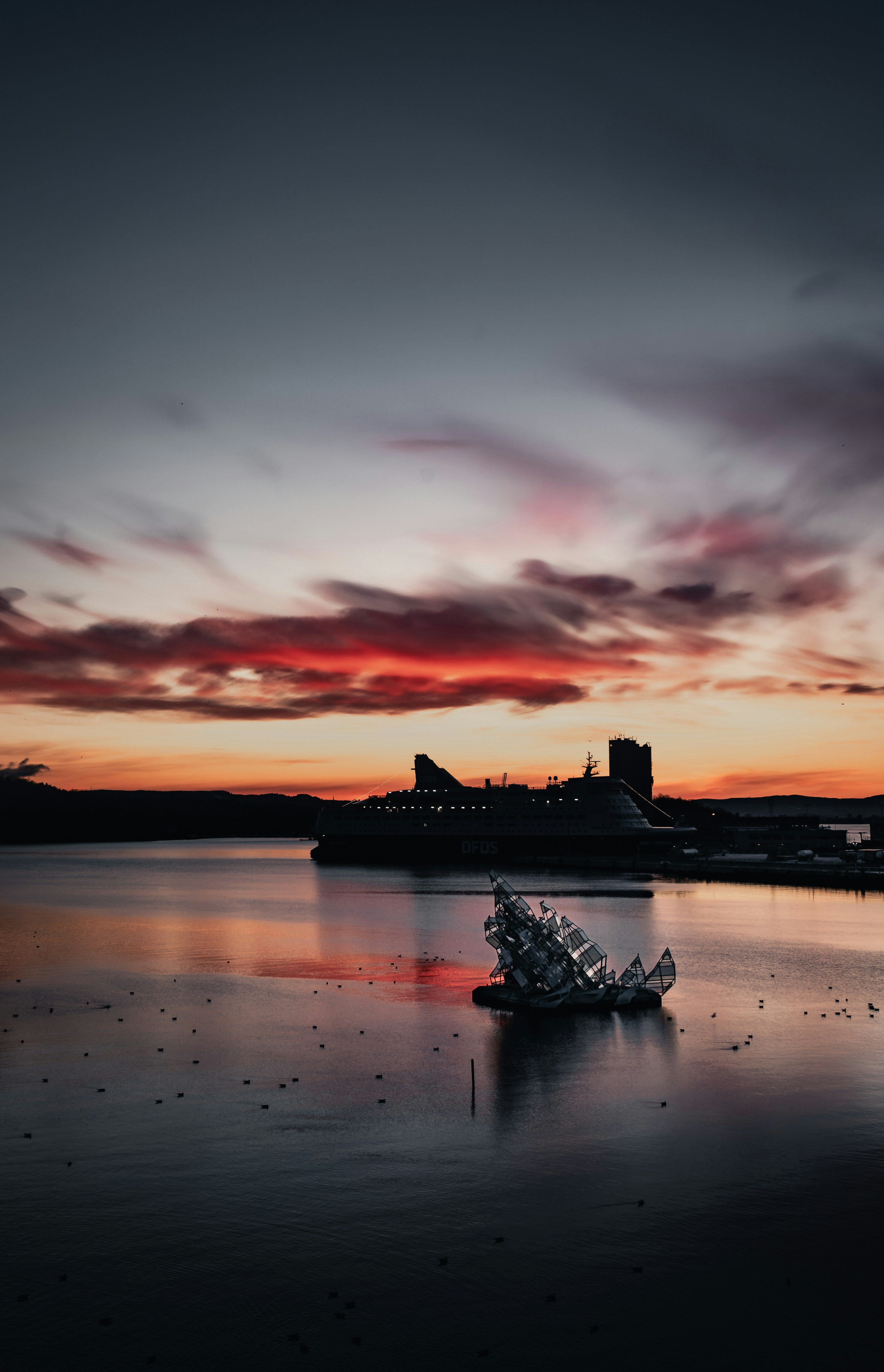 Dusk Harbor: A Cruise Ship Silhouette Framed by a Glass-Faceted Sculpture