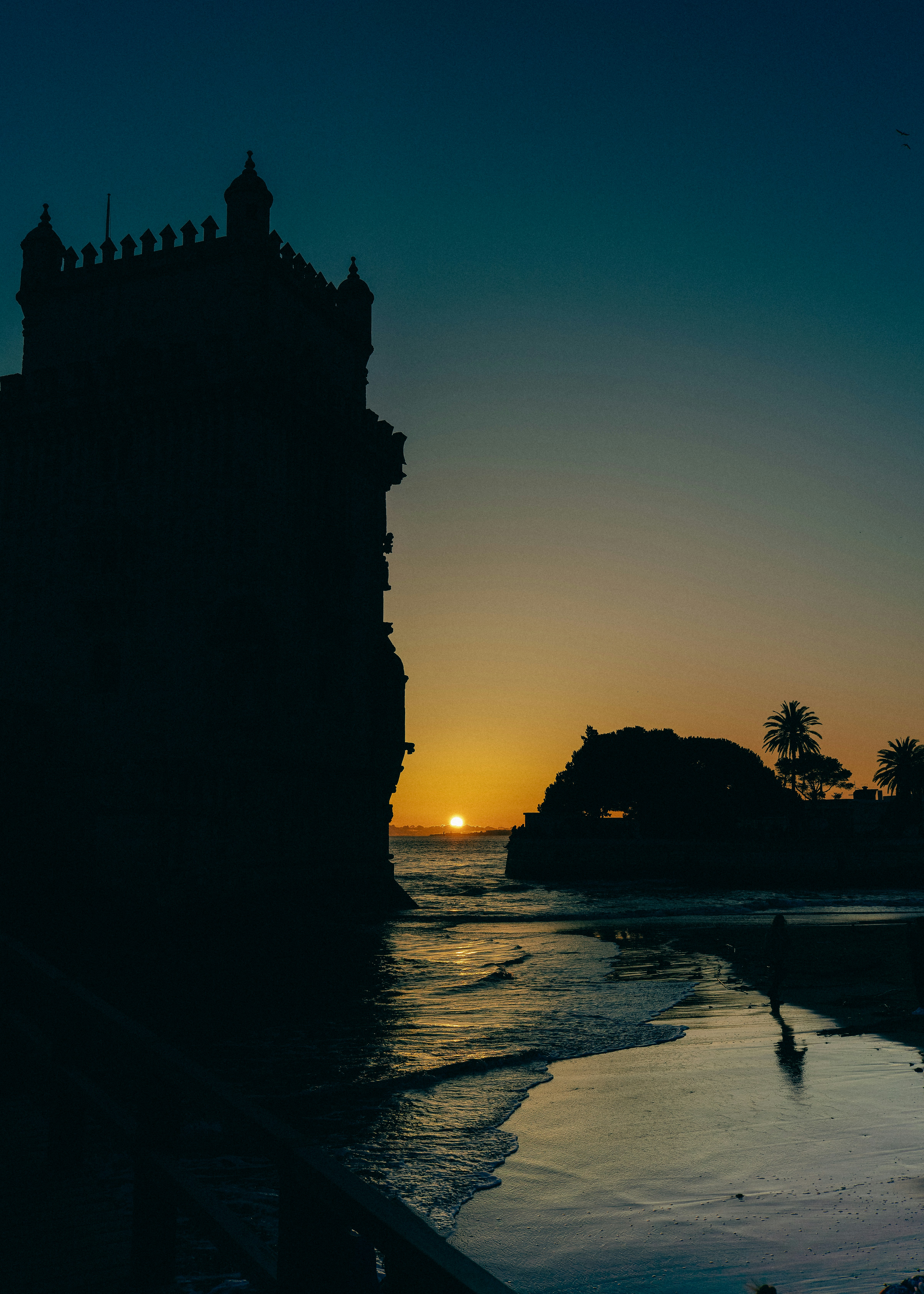 Sunset silhouette: fortress tower over a tranquil shoreline