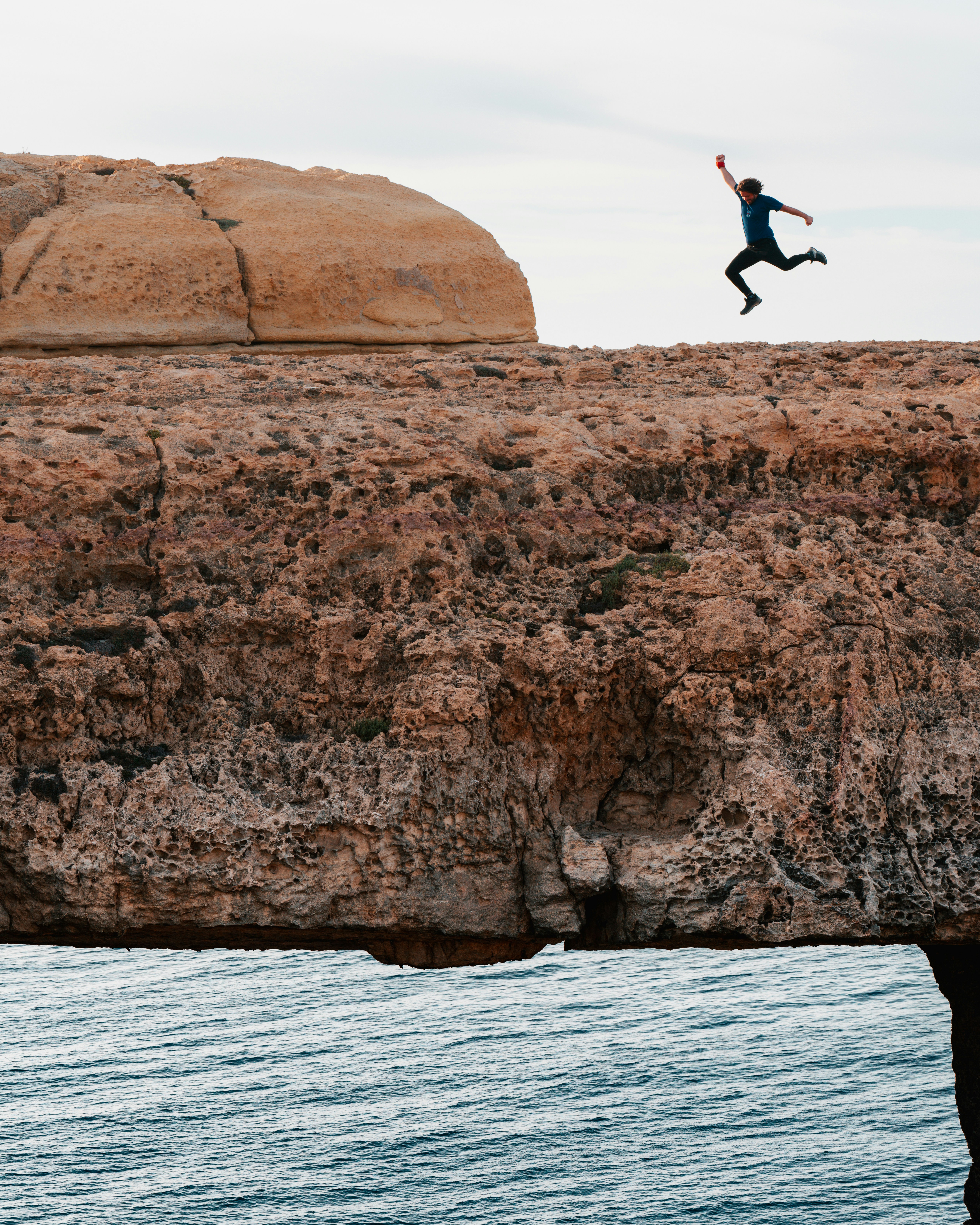 Adventurous Leap Over Natural Arch