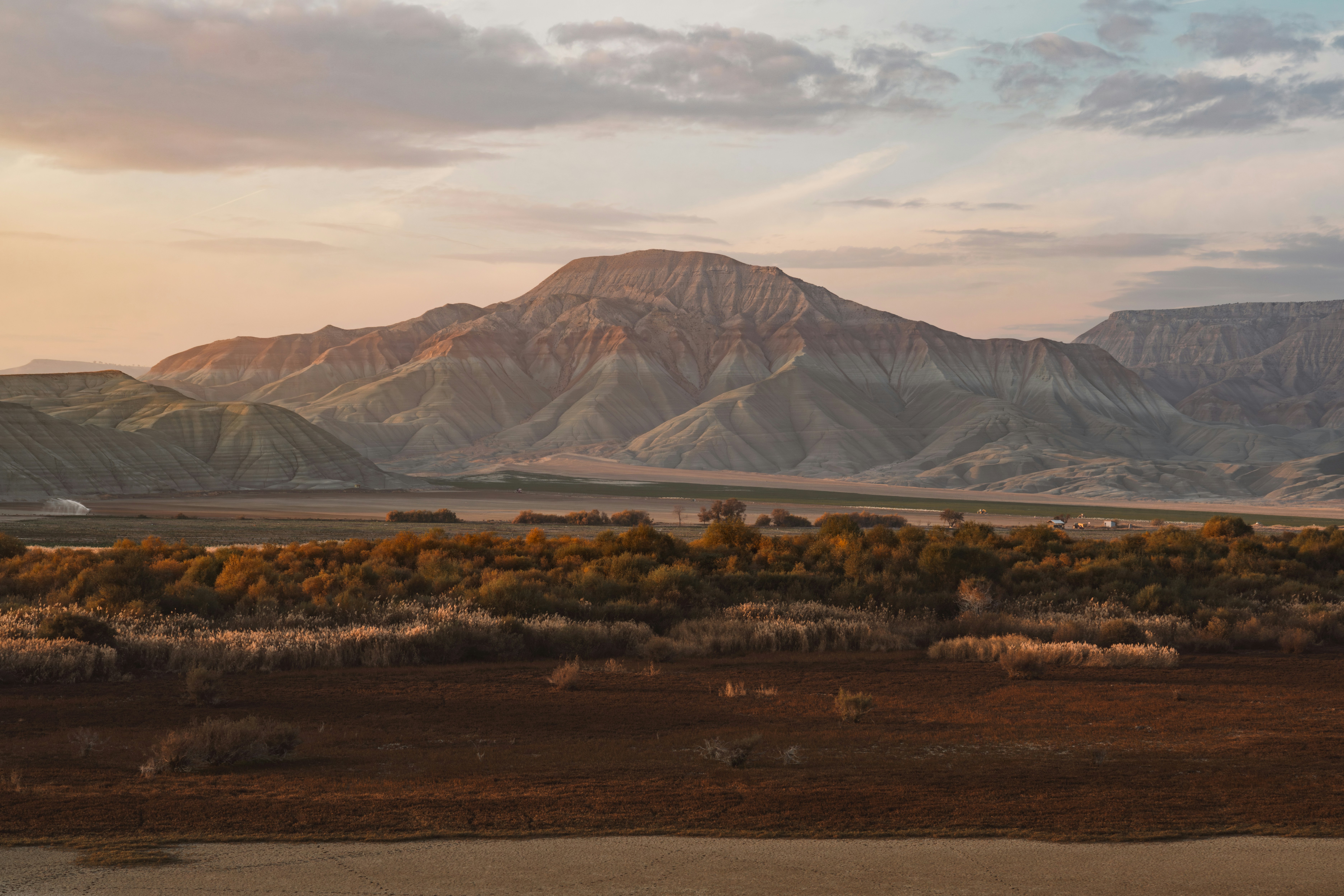Mountain range illuminated by the warm hues of sunset, with contrasting earthy tones and soft golden light.