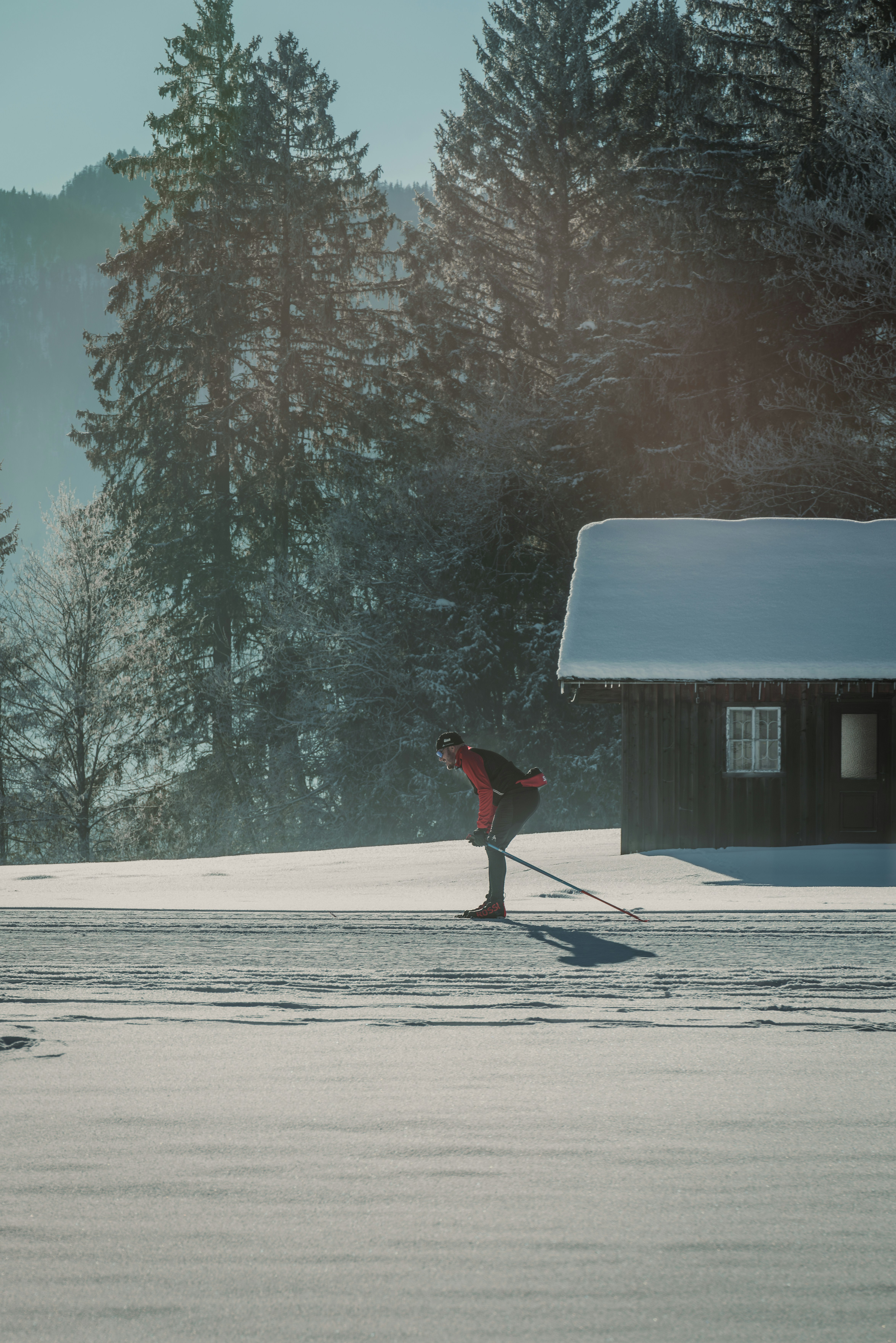 Lone Skier Tracing a Quiet Line Past a Snow-Covered Cabin